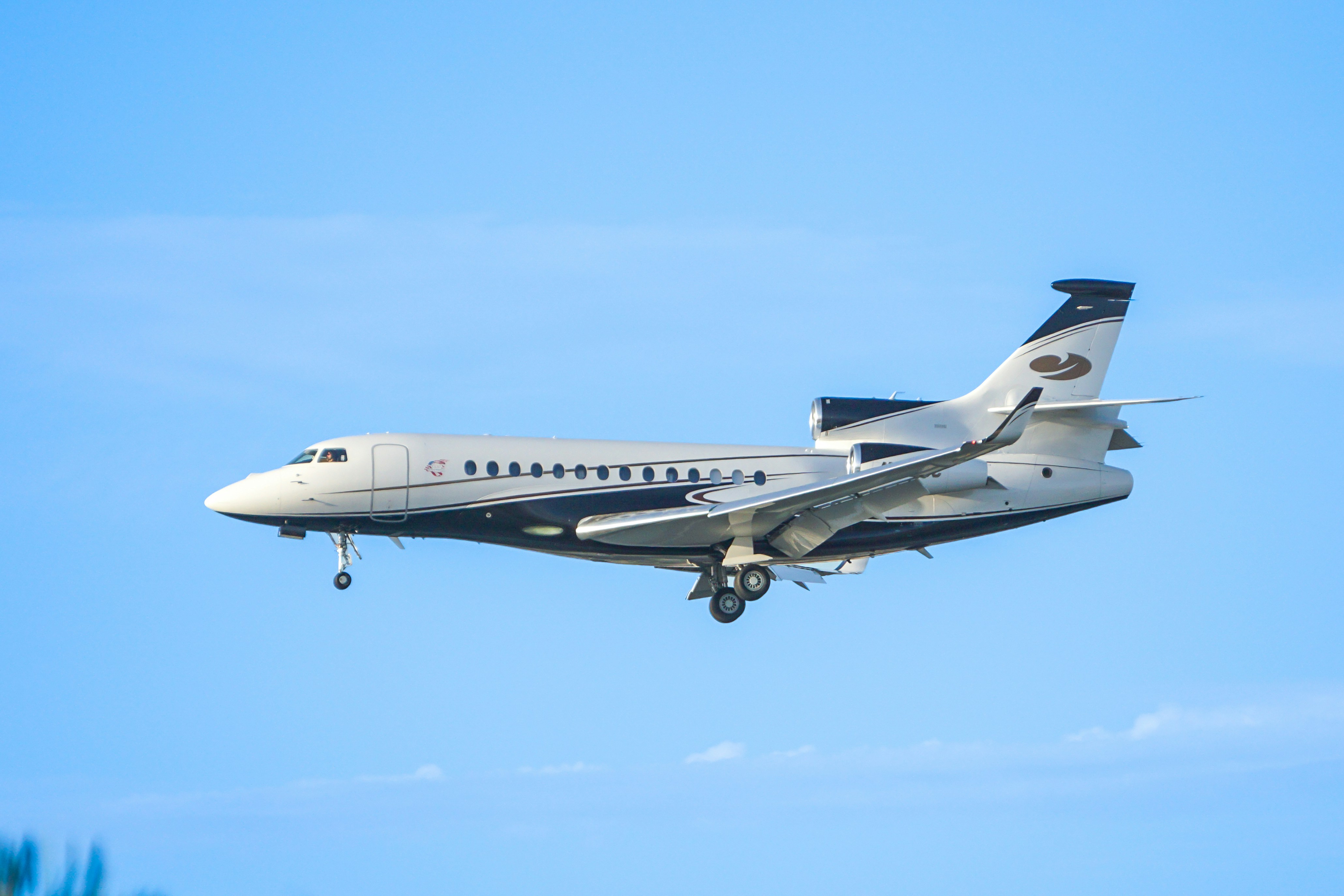 A midflight silhouette: business jet gliding under a pale blue sky