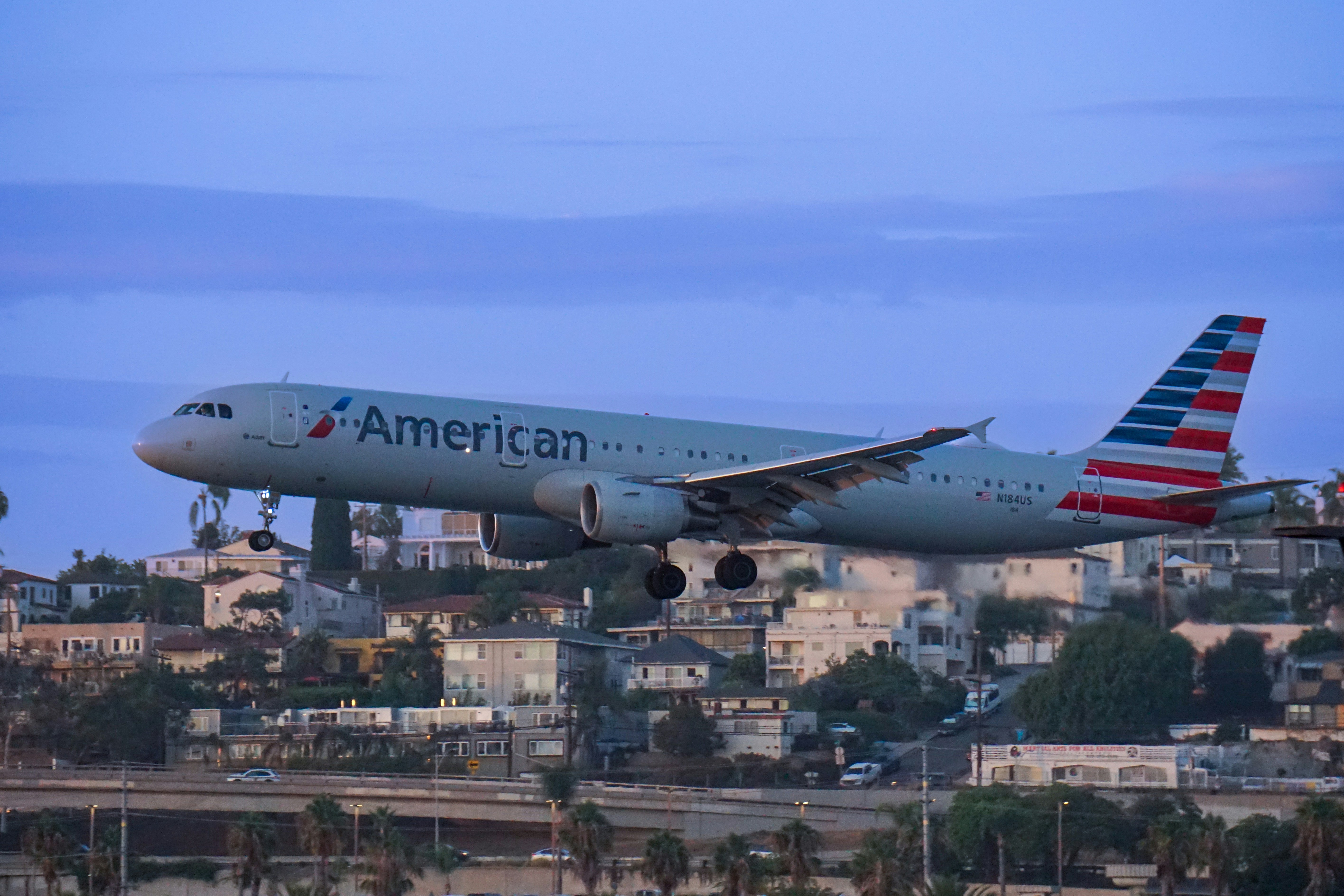 Airliner in descent above a sunlit coastal town