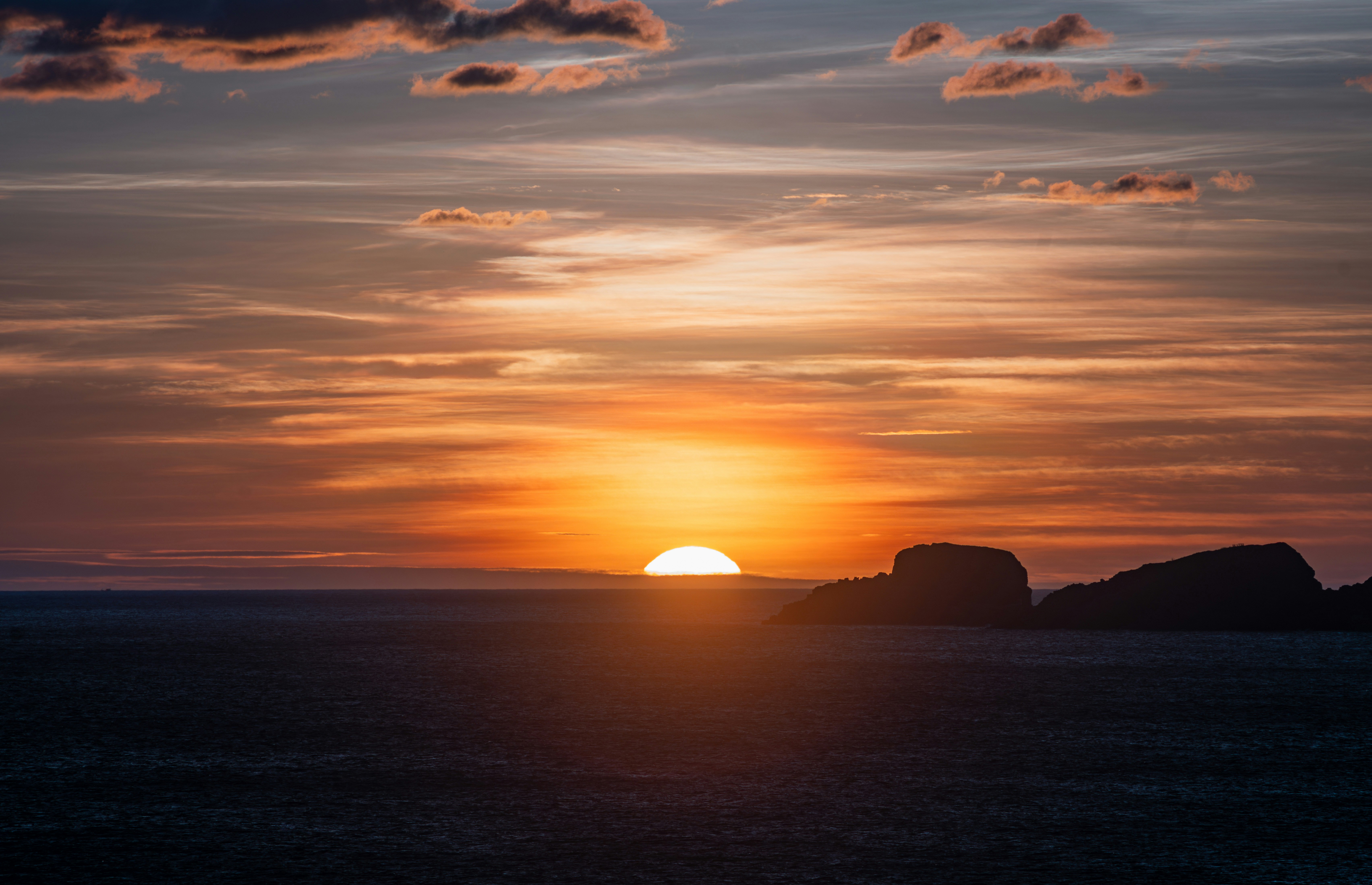 Sun Dipping Behind a Silhouette: A Gentle Ocean Sunset