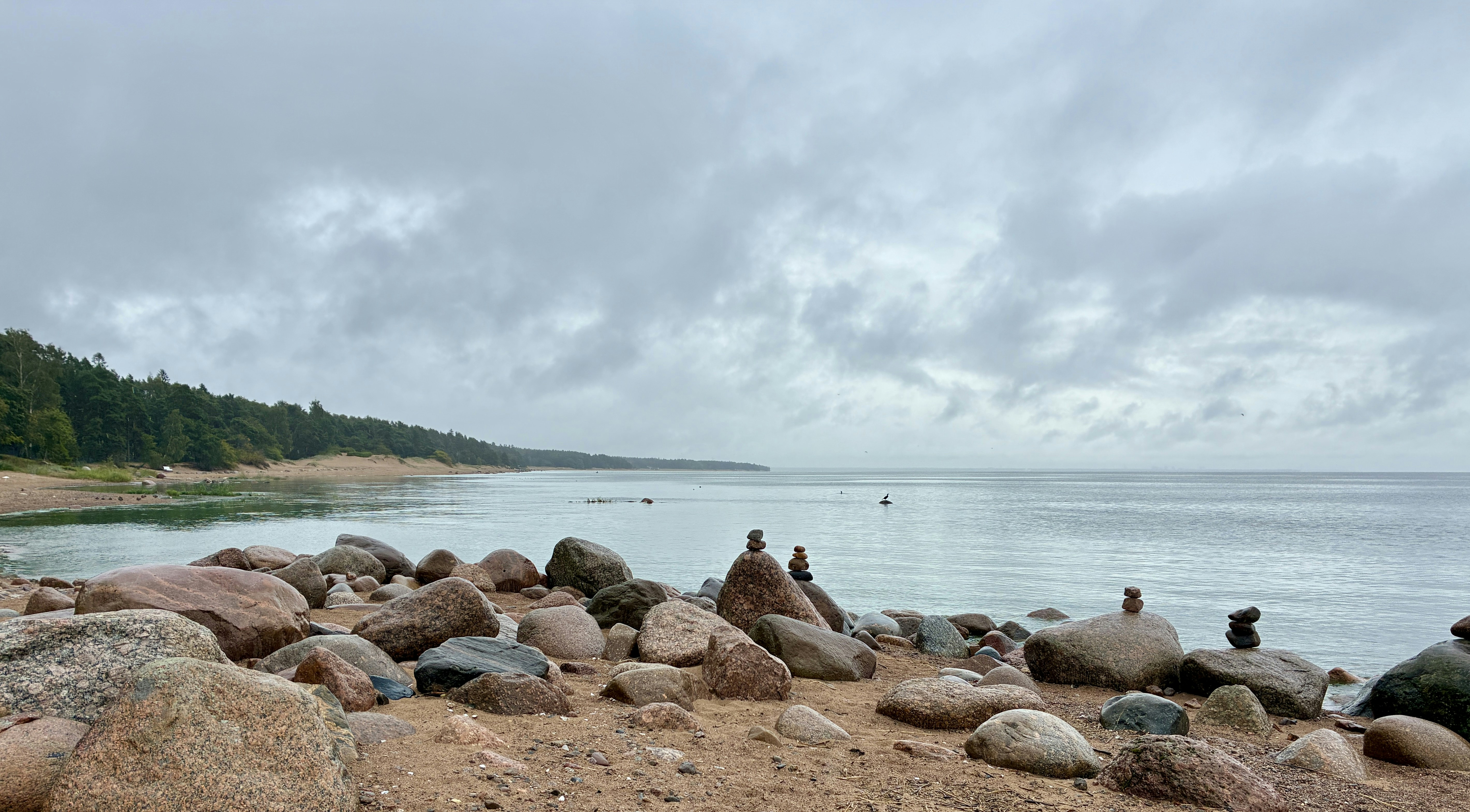 Pebble shoreline at tranquil sea under overcast skies