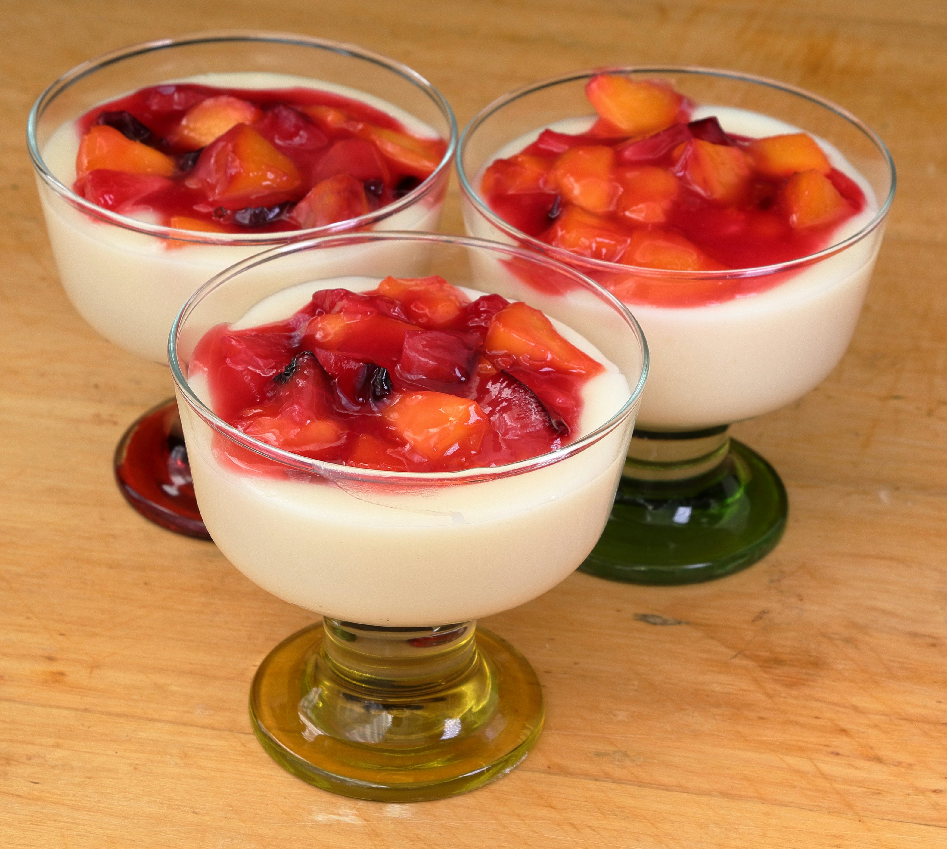 Three Creamy Panna Cuddles: Fruit-Topped Desserts on Glass Pedestals