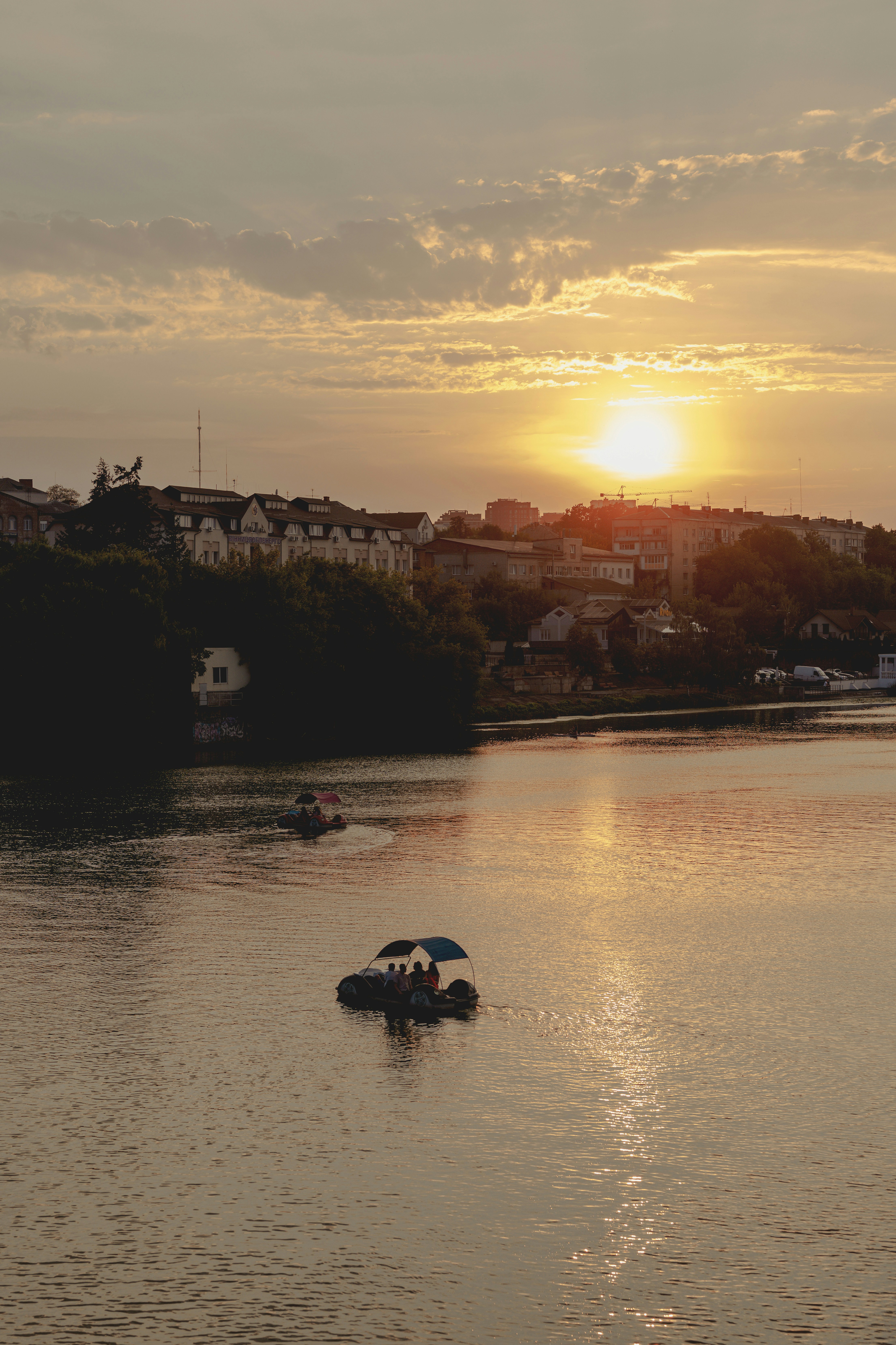Sunlit river ferry at dusk over a calm town