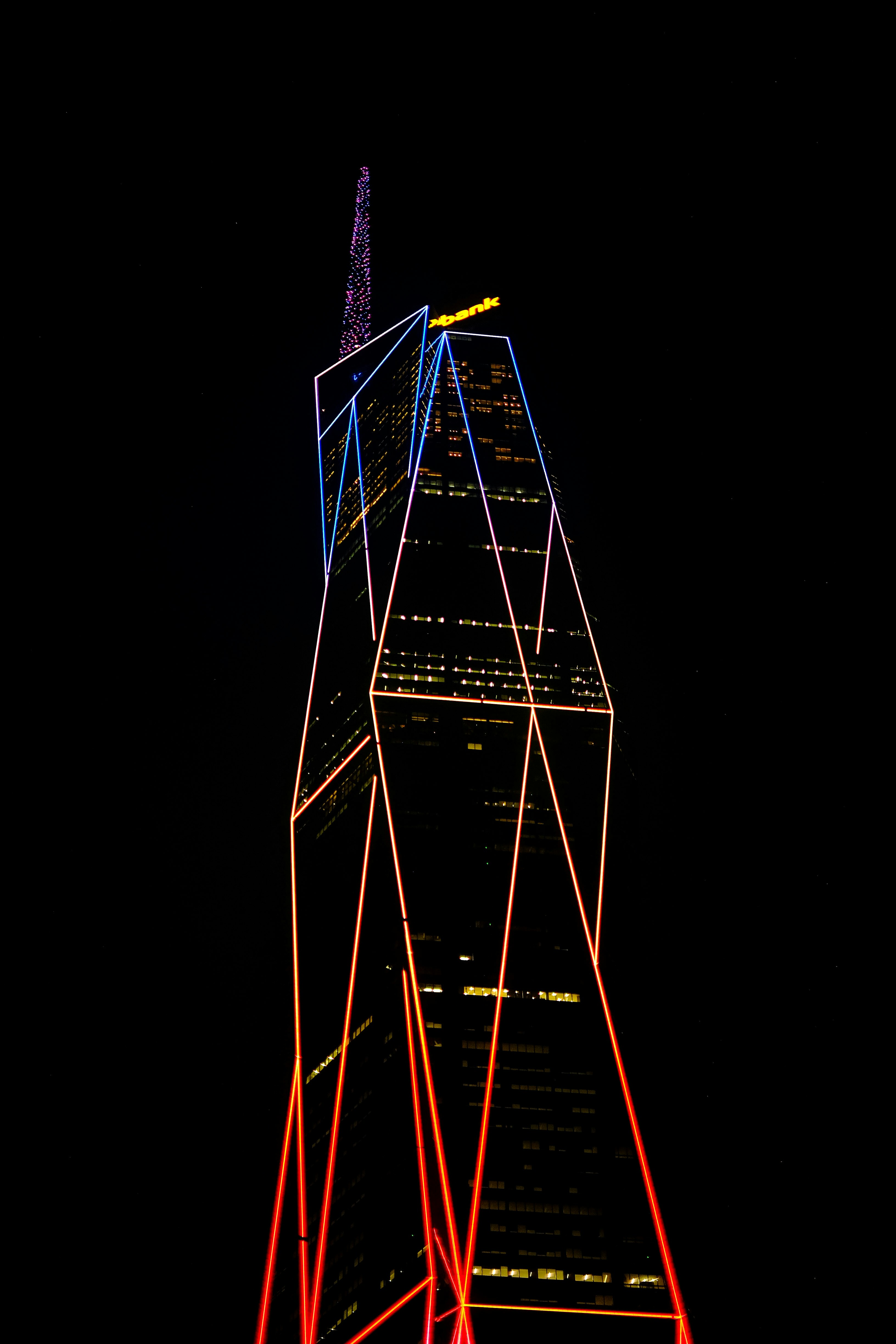 Neon-edged Skyward: The Faceted Tower Illuminated at Night