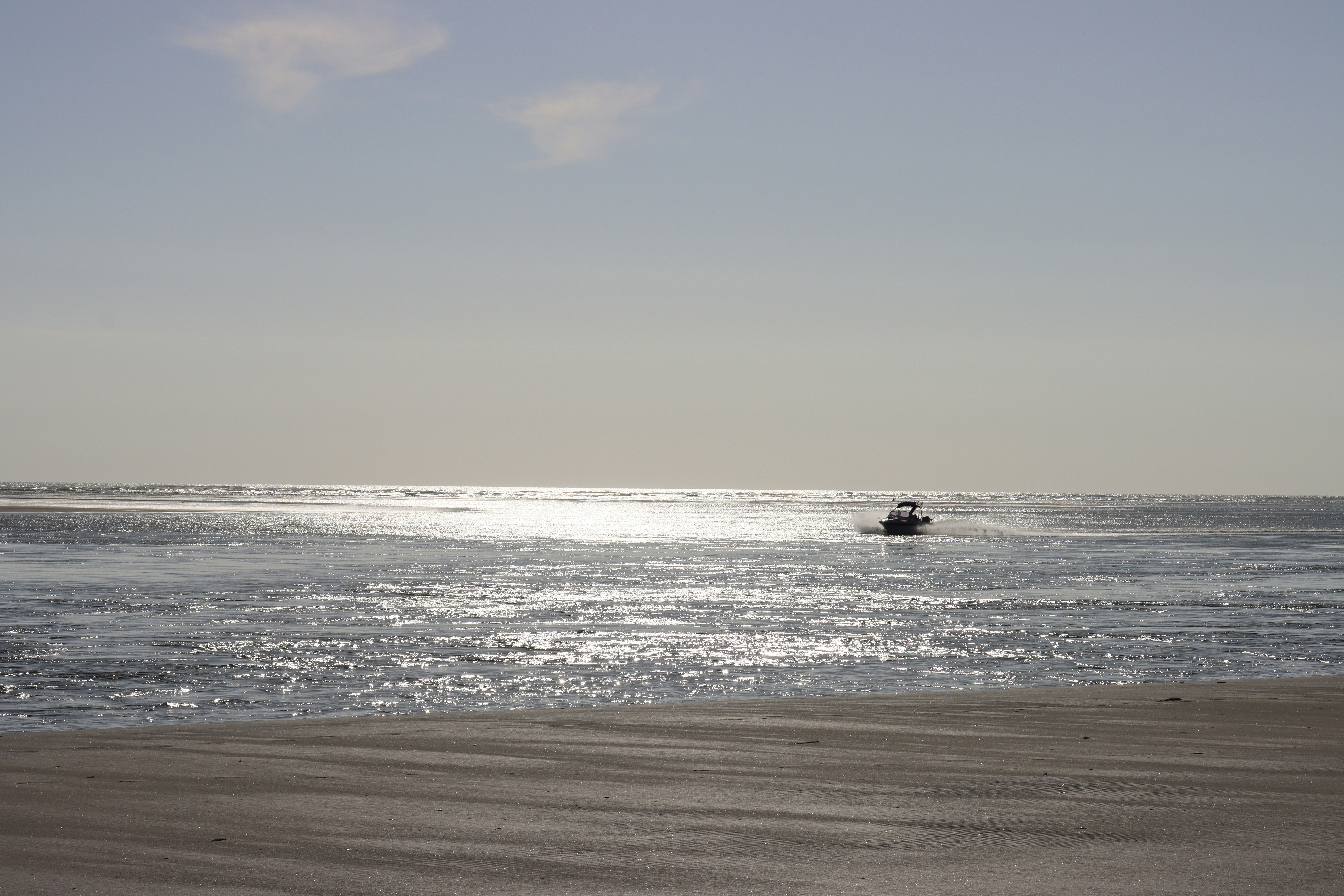 Sunlit Sea and Distant Boat on a Quiet Beach