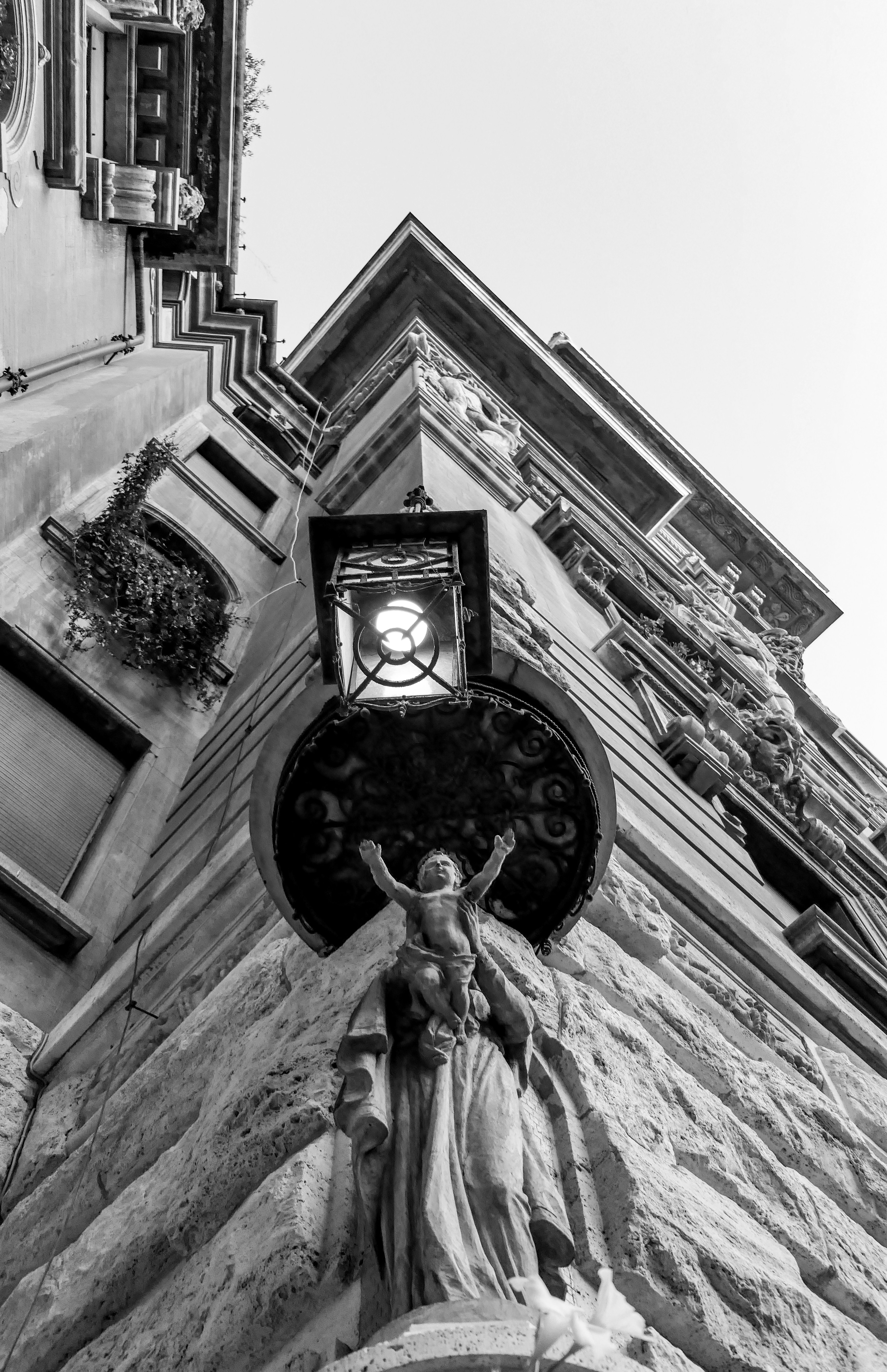 Stone Angel Under Street Lantern: A Tilted Facade in monochrome