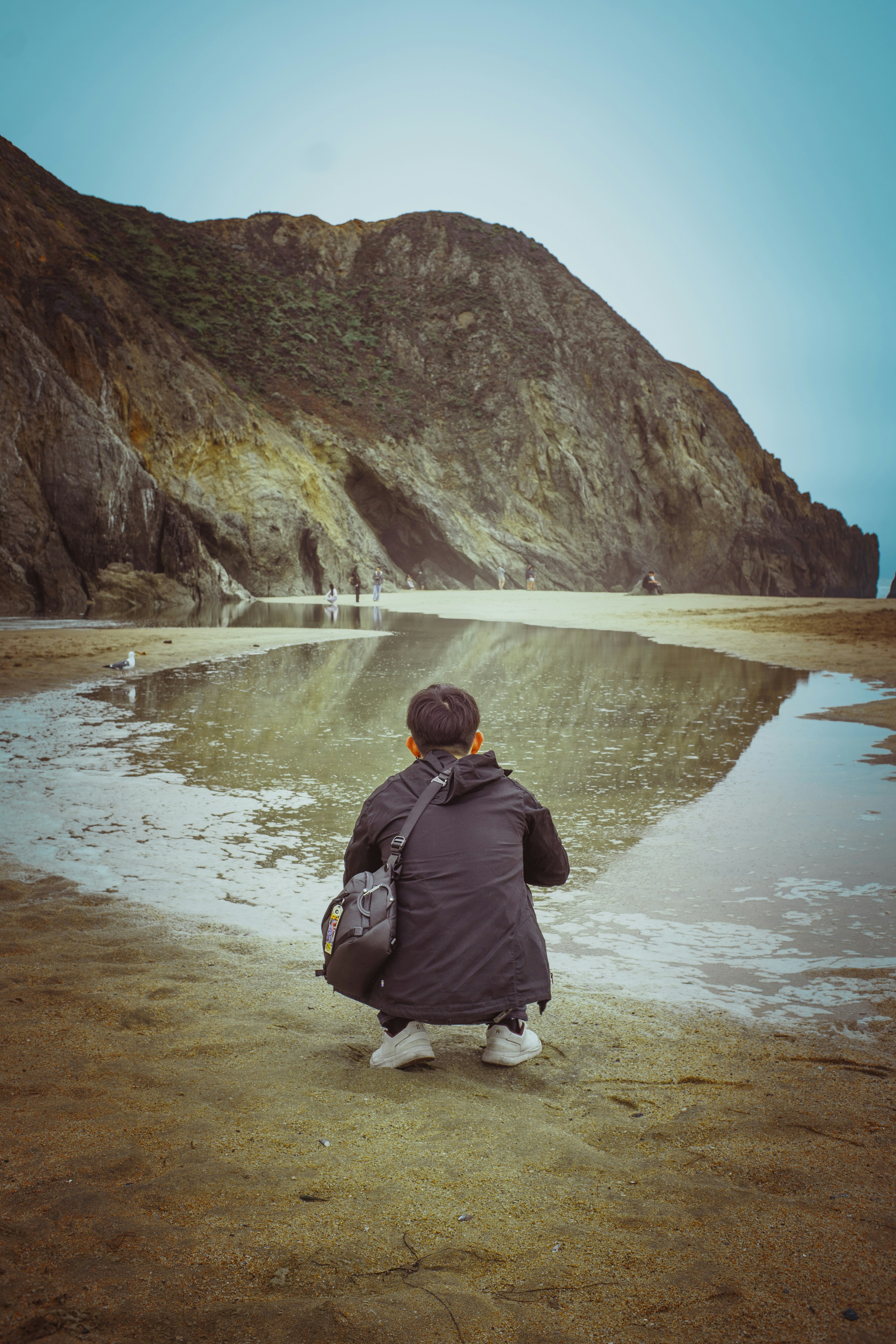 Shoal of Reflections: A lone photographer crouches at the shoreline