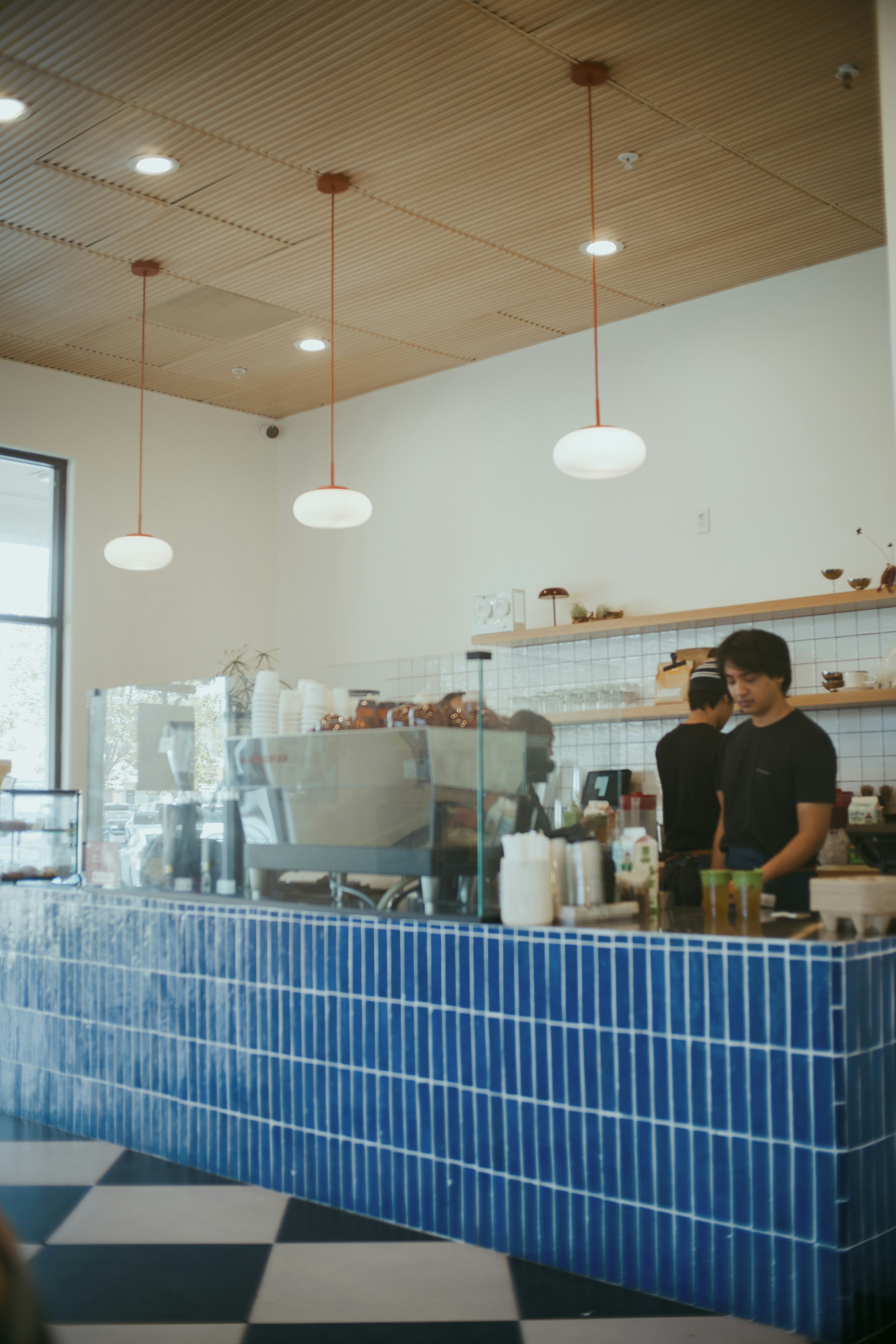 Cafè Counter Warmth: Baristas at Work Behind Glass