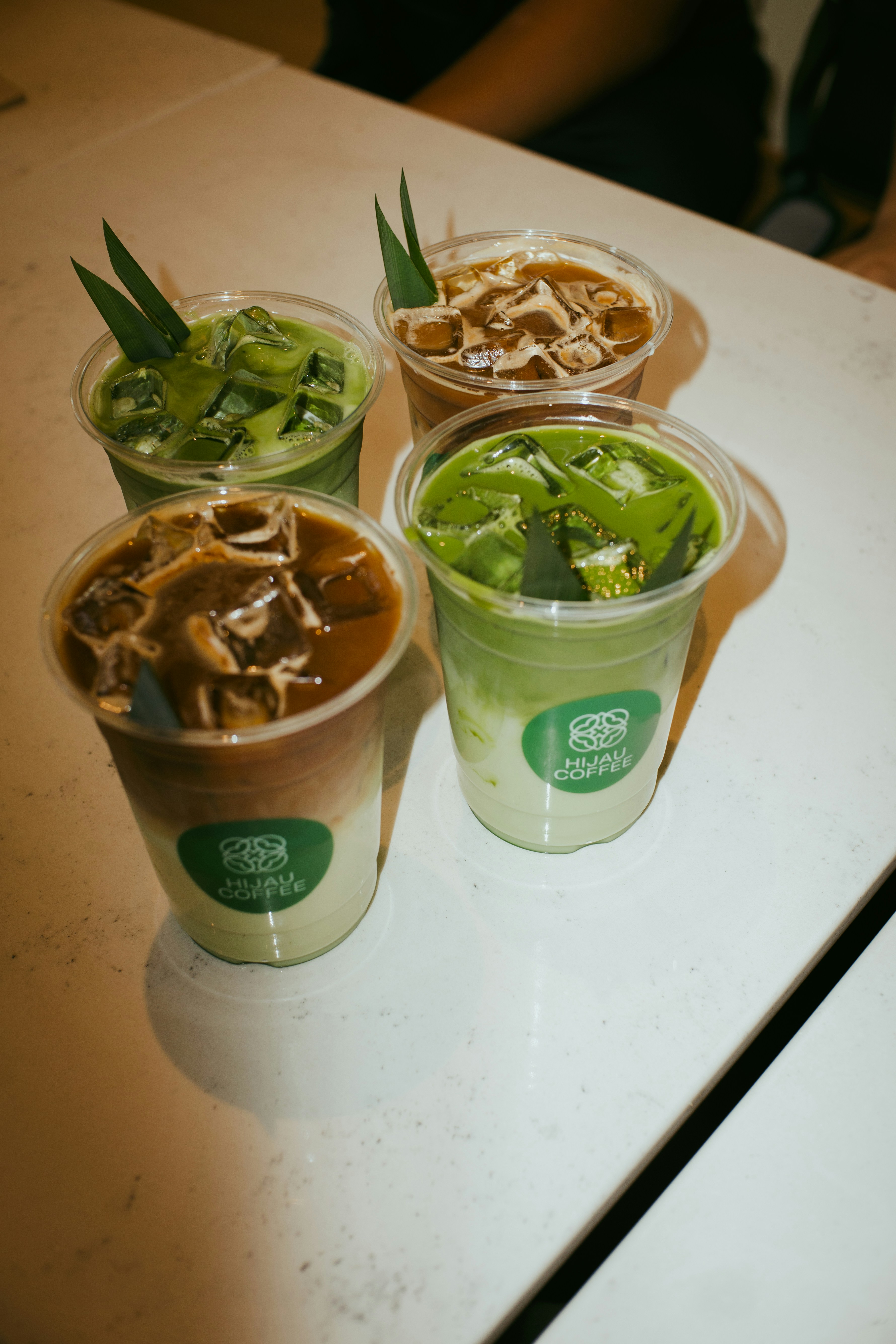 Four iced beverages in clear cups arranged on a white tabletop