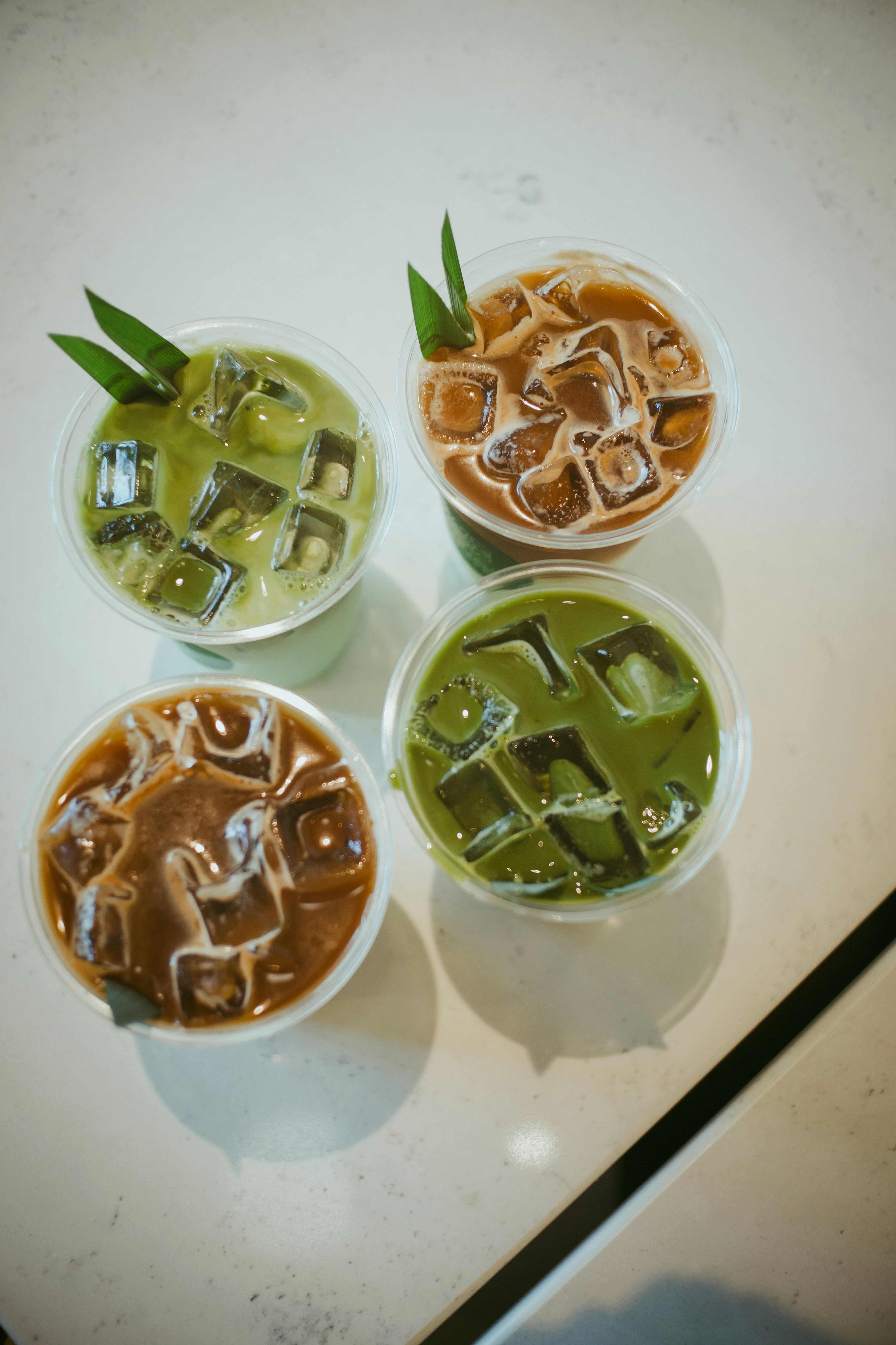 Quadruple Ice-Cooled Teas: Aerial View of Four Lime and Matcha Drinks on a Marble Bar