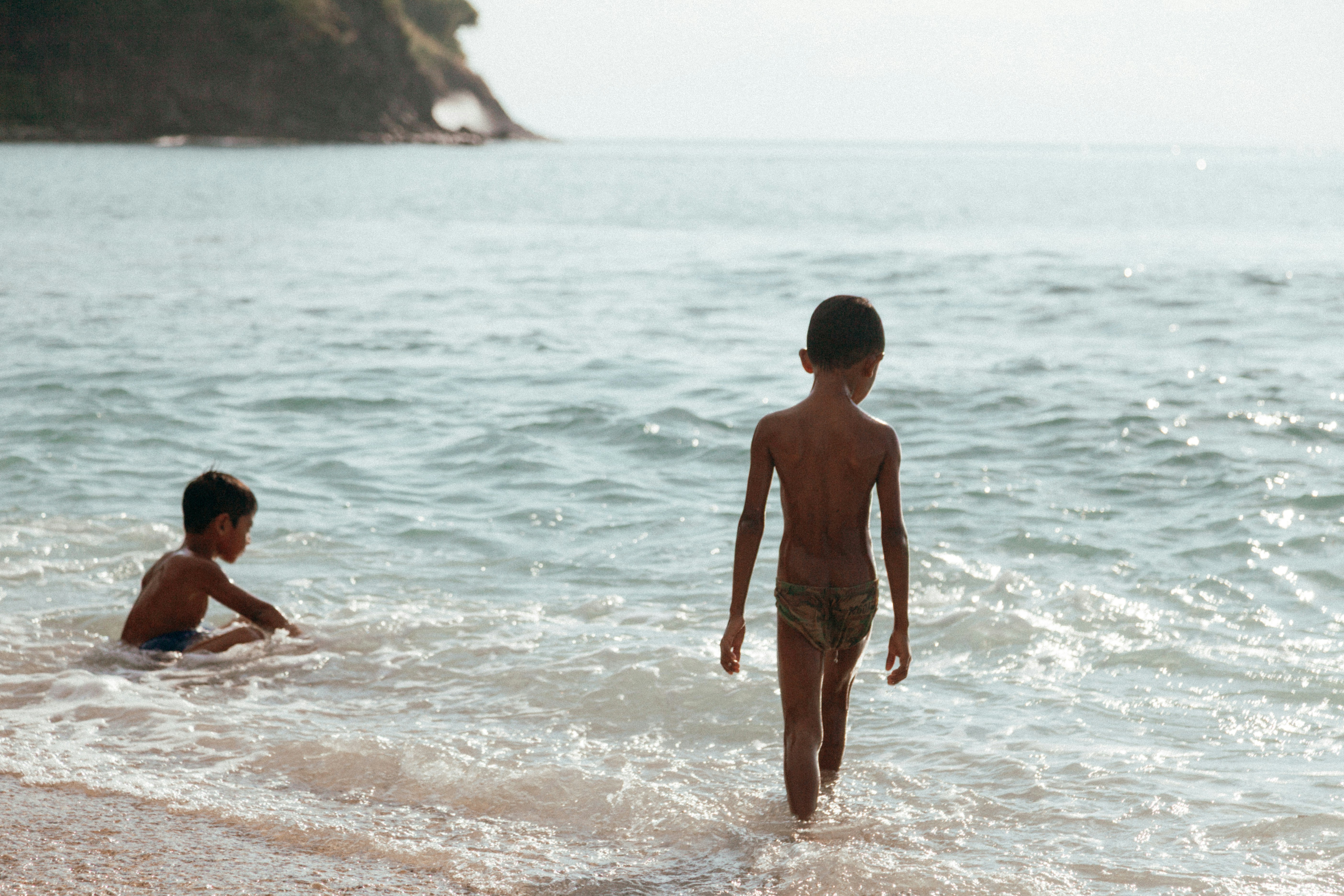 Sunlit Shore: Boys at the Break in Clear Seawater