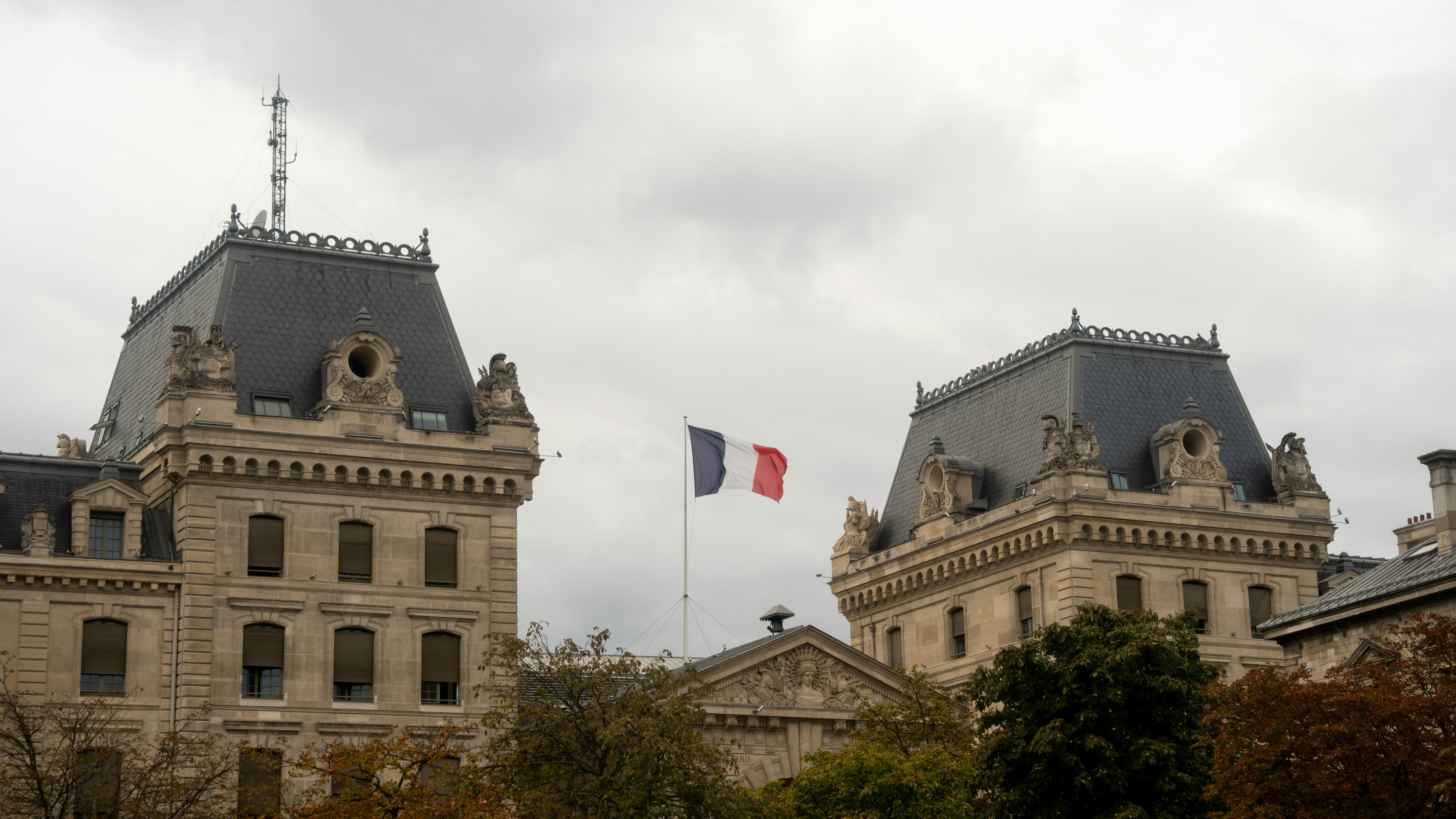 French Flag Over Historic Facades: Symmetry Under a Clouded Sky