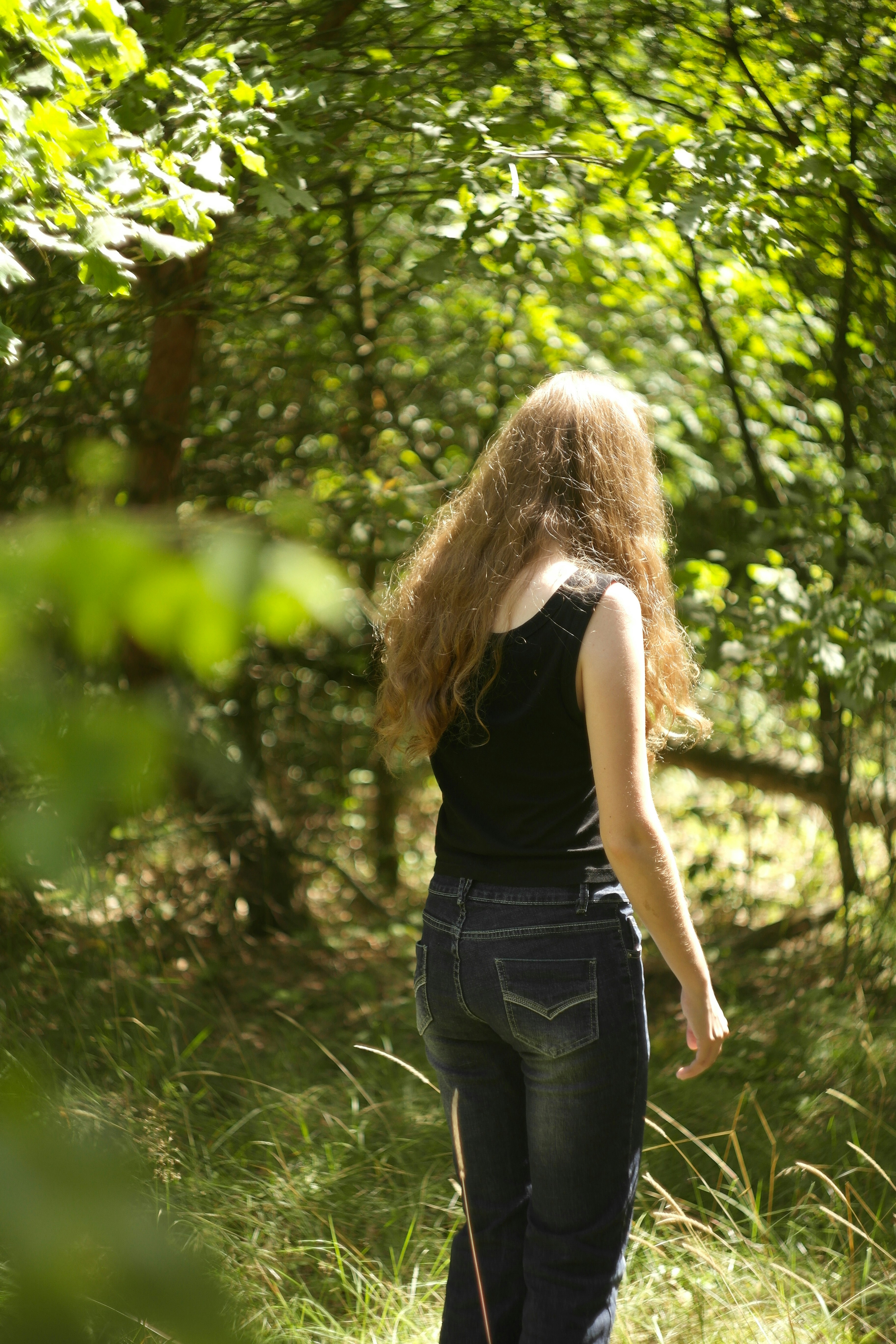 Sunlit Forest Portrait: A Woman Walks Into the Green Glow