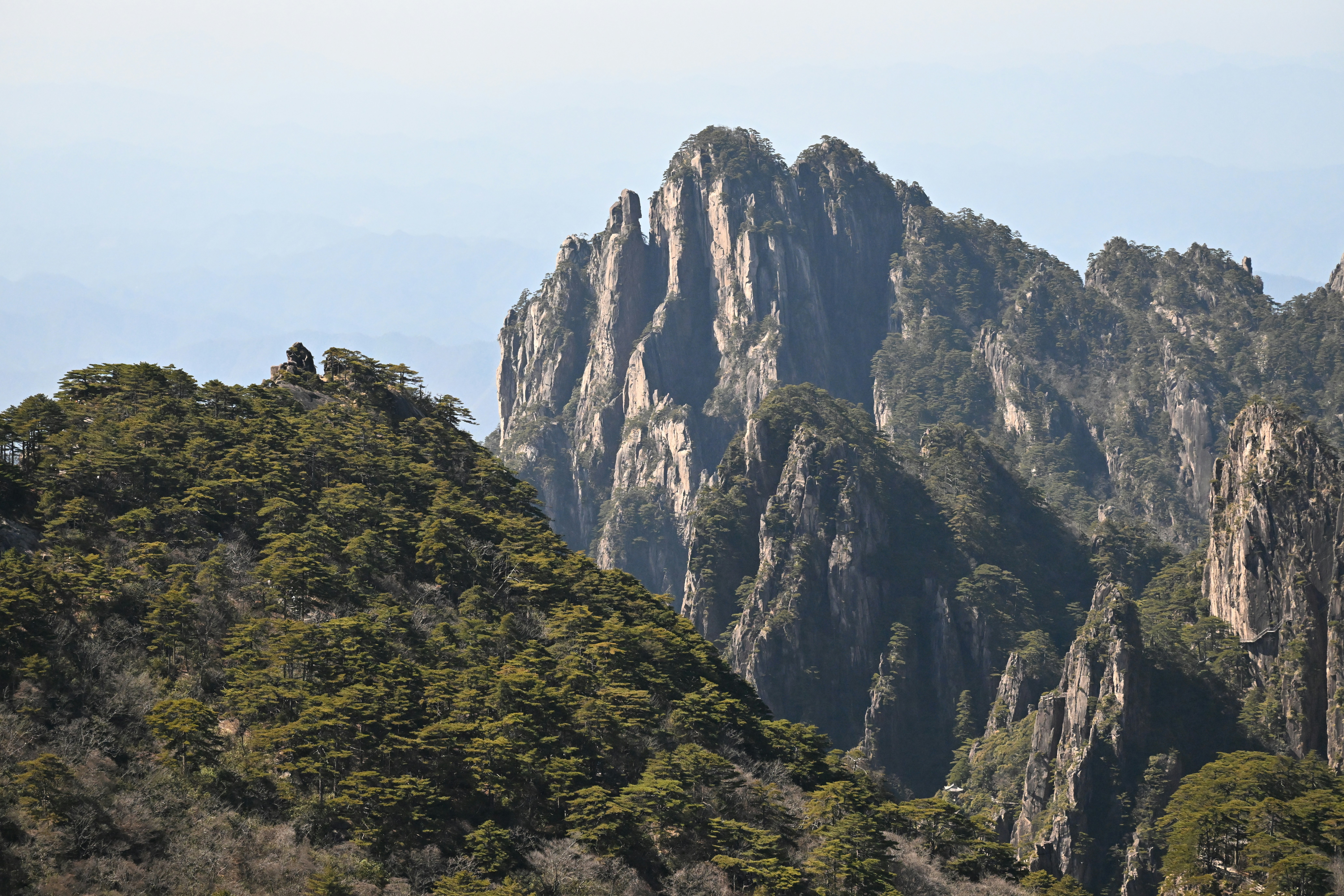 Towering granite sentinels behind a pine-clad hillside