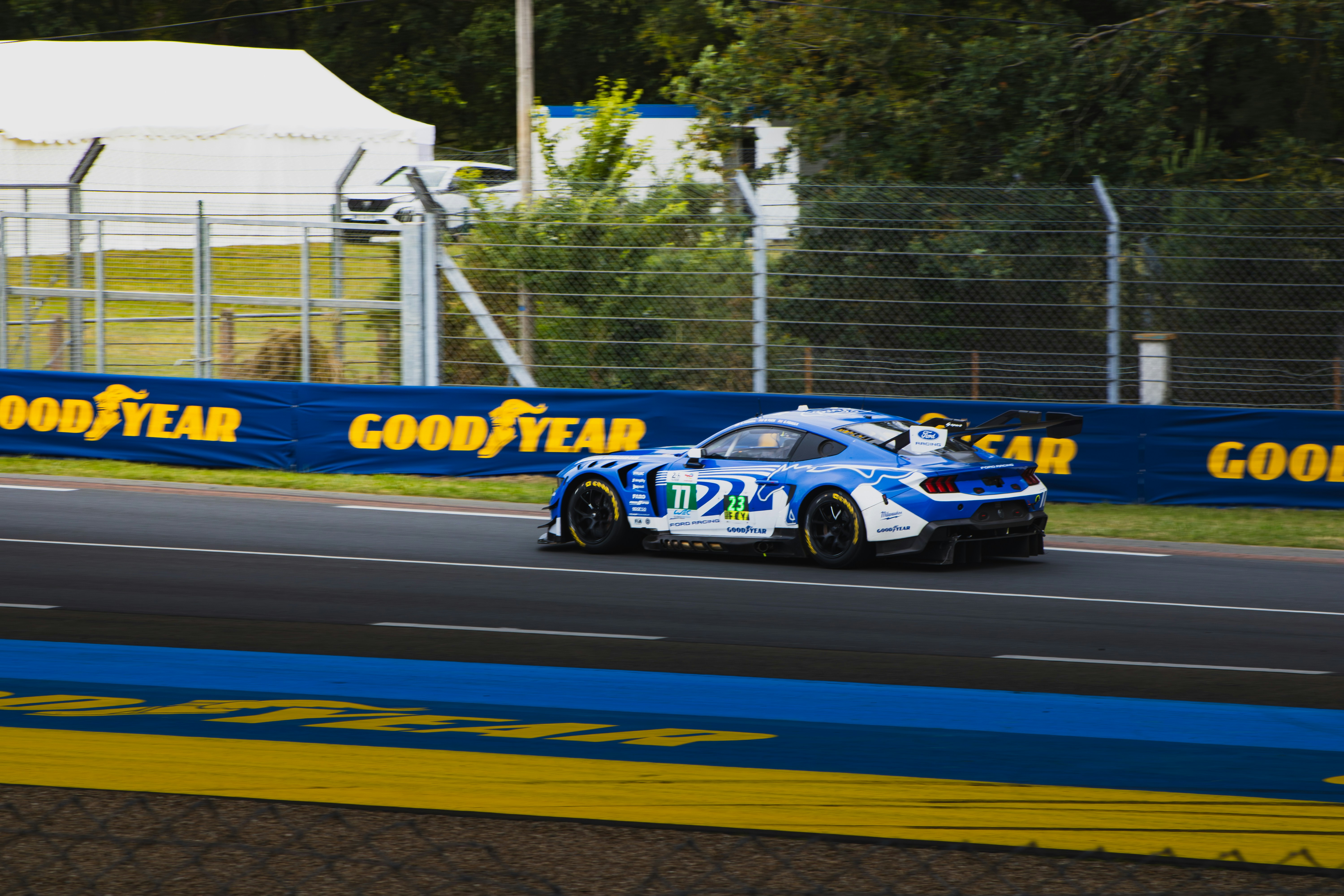 Blue-and-white race car slicing through pit-wall to apex
