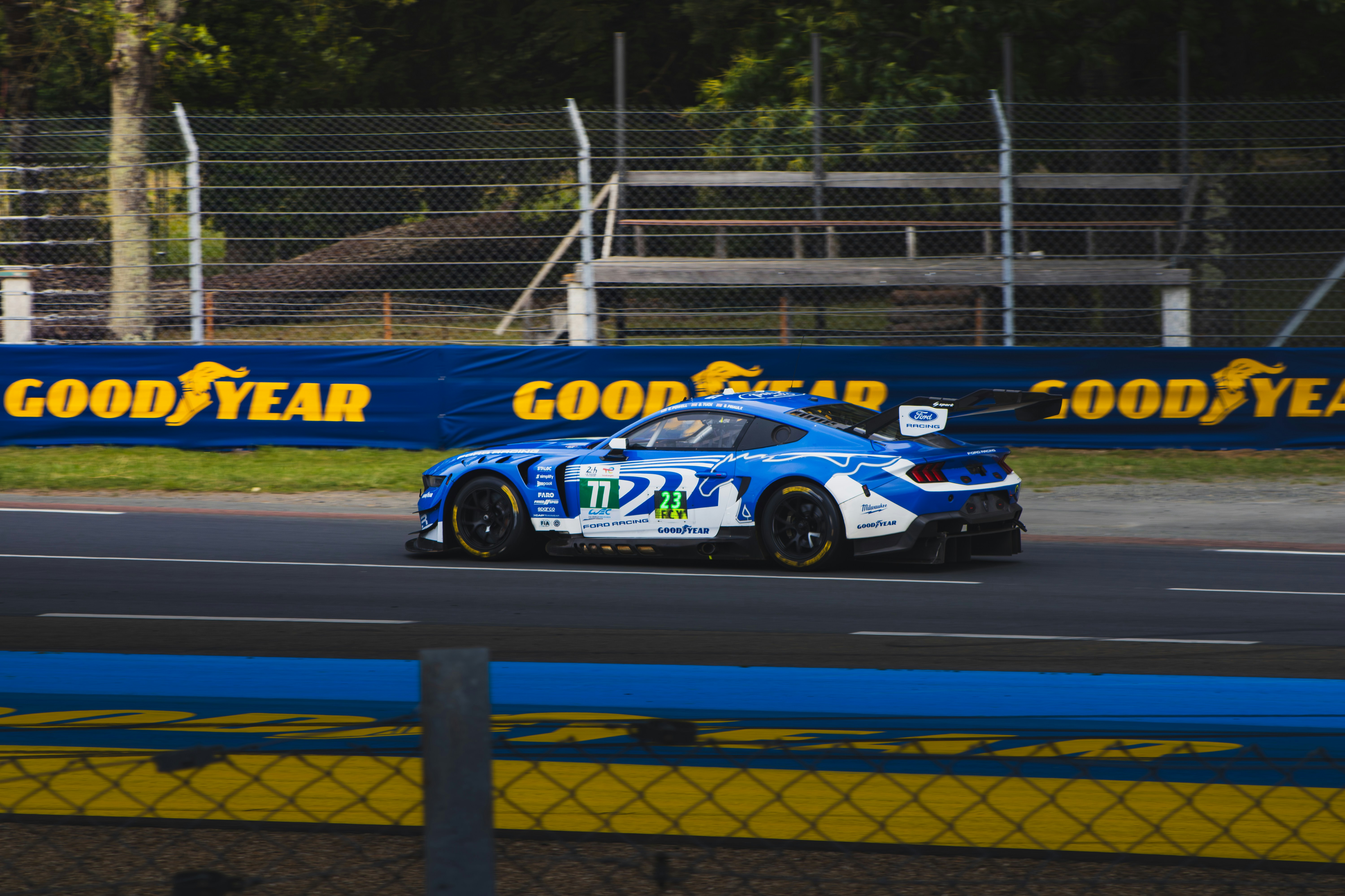 Blue race car in motion along a Goodyear bannered track