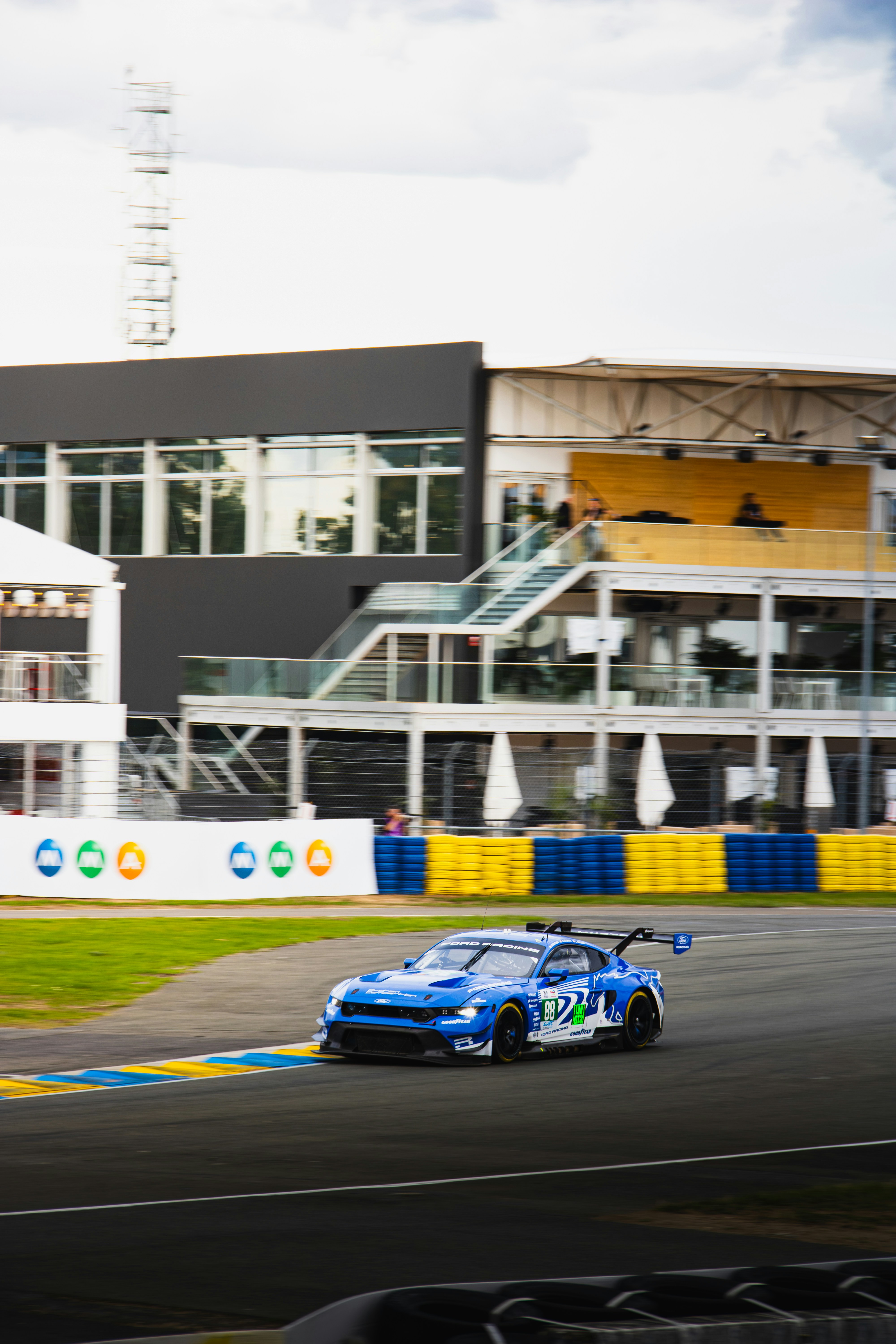 Blue race car carving through the chicane at a sunlit circuit