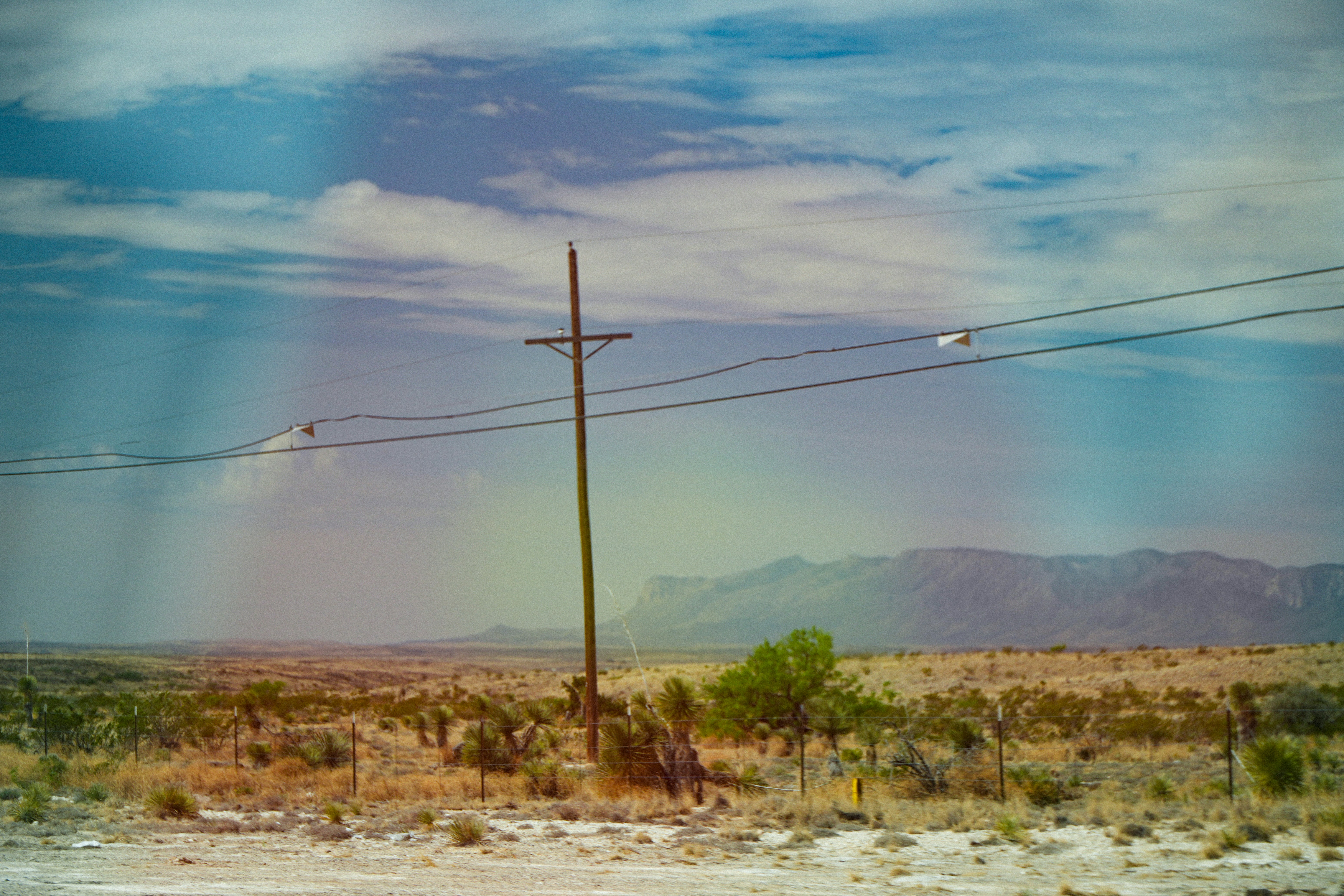 Desert Power Line under a Quiet Rainbow Horizon