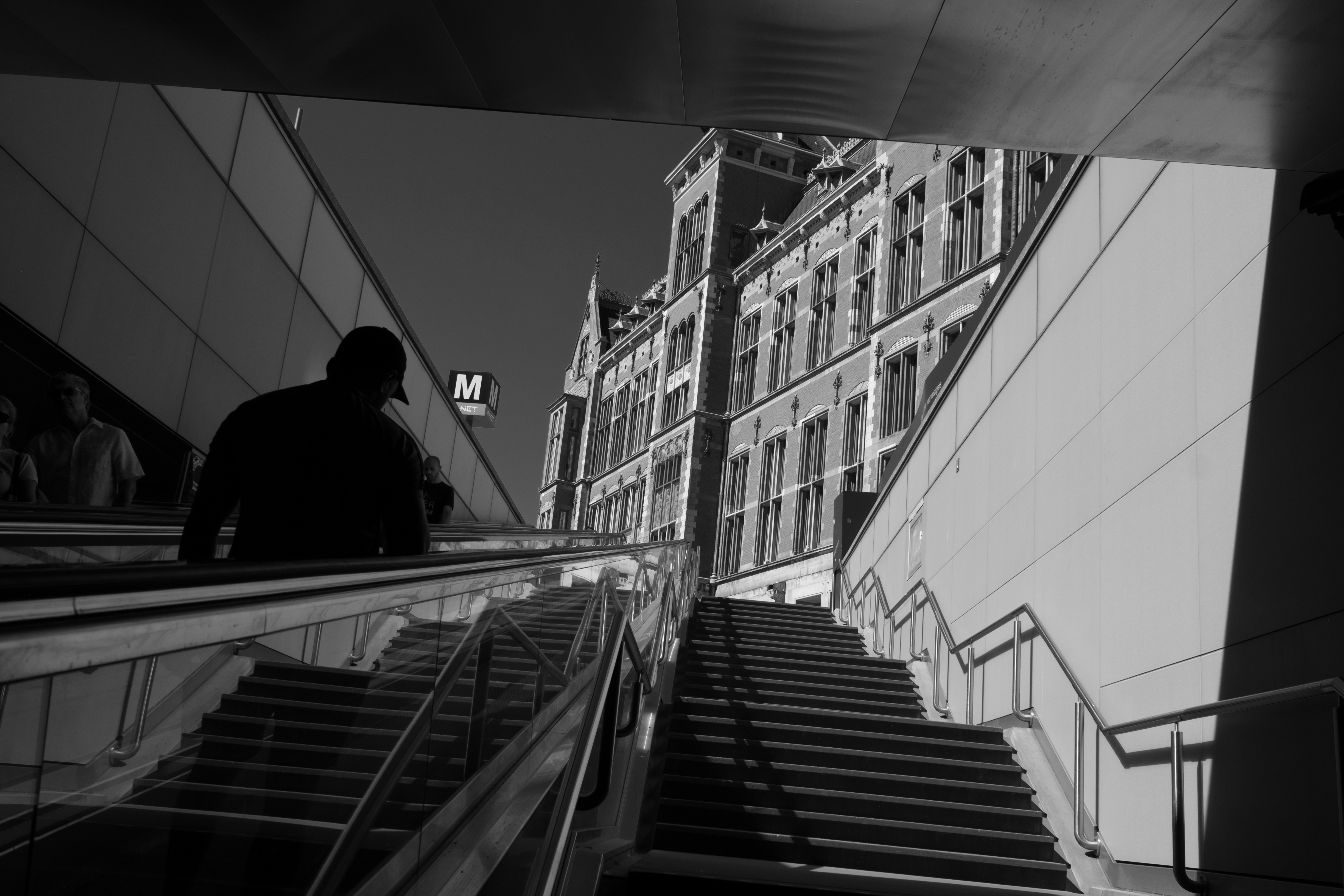 Urban Ascent: A Lone Figure Traverses the Shadowed Escalator