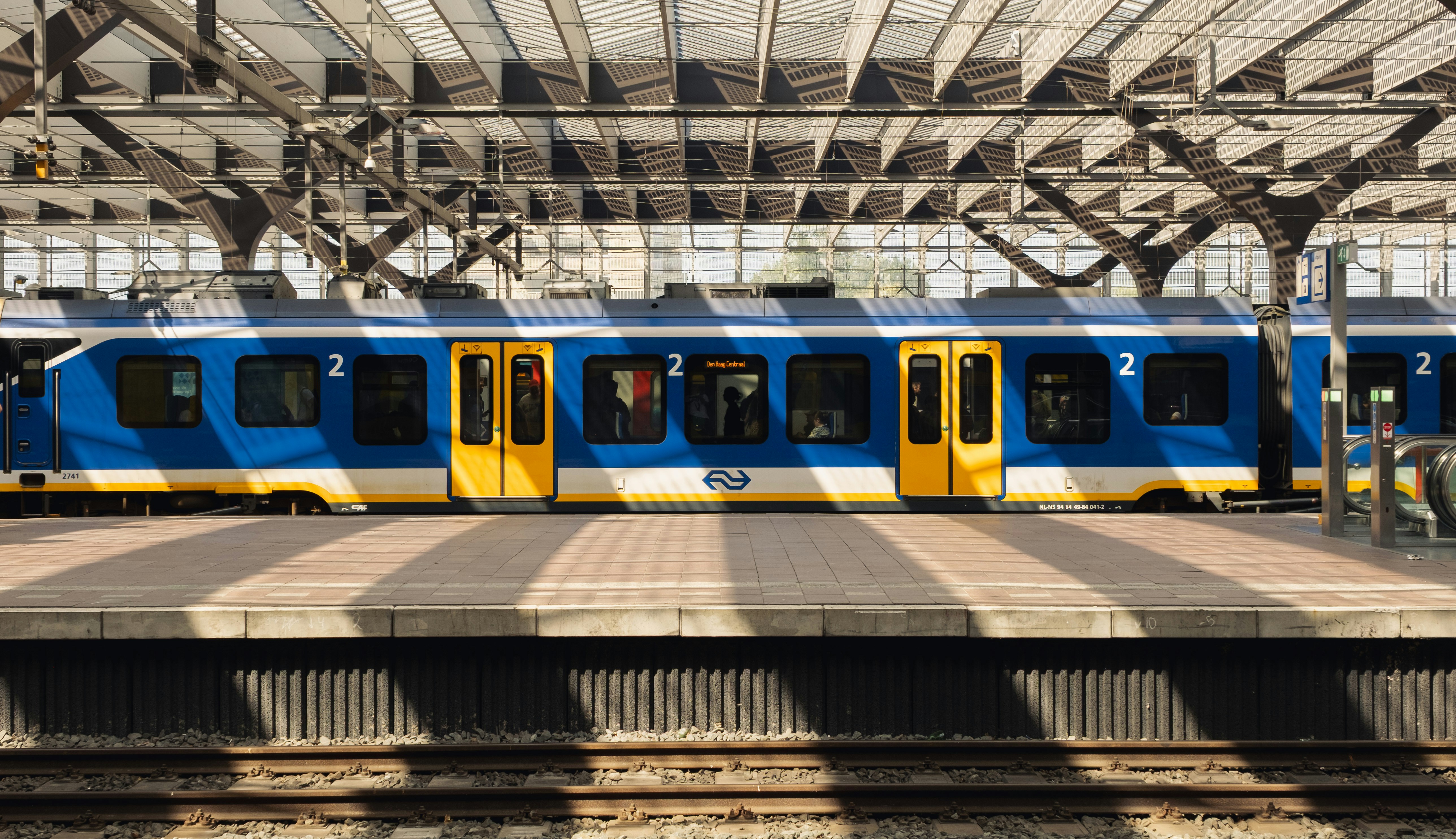 Blue and Yellow Commuter: A Quiet Moment on a Sunlit Platform