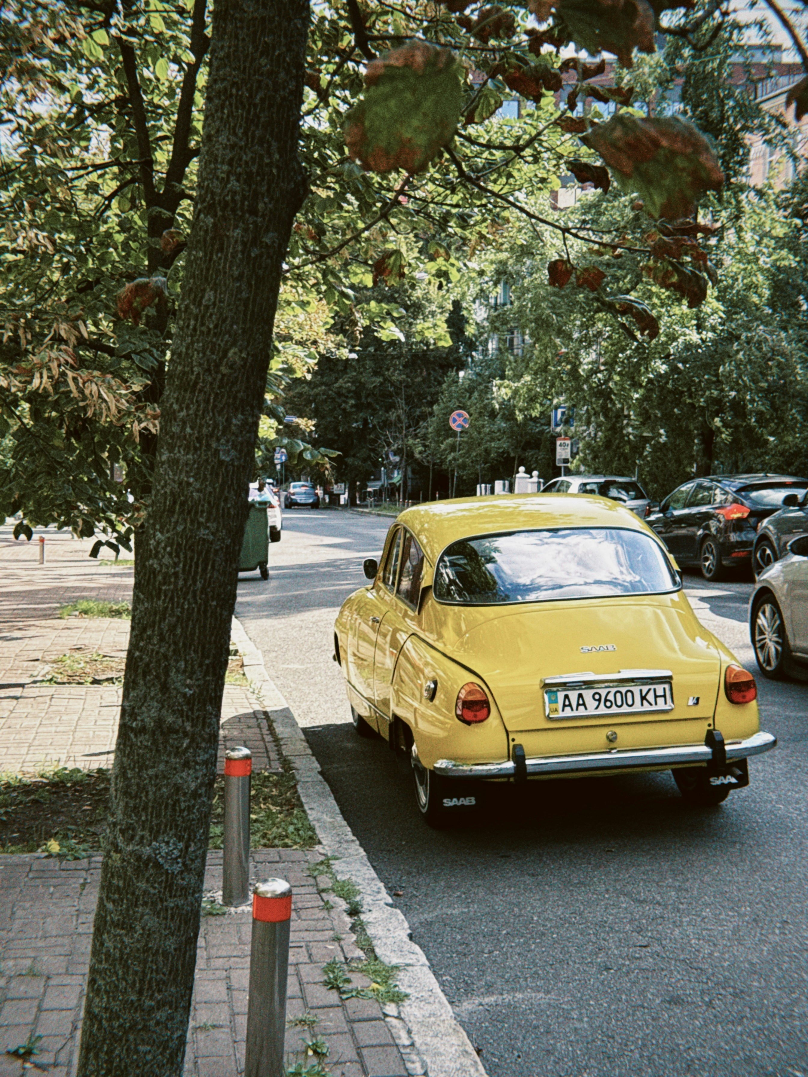 Yellow Classic: A Retro Saab Stalls Along a Tree-Lined Street