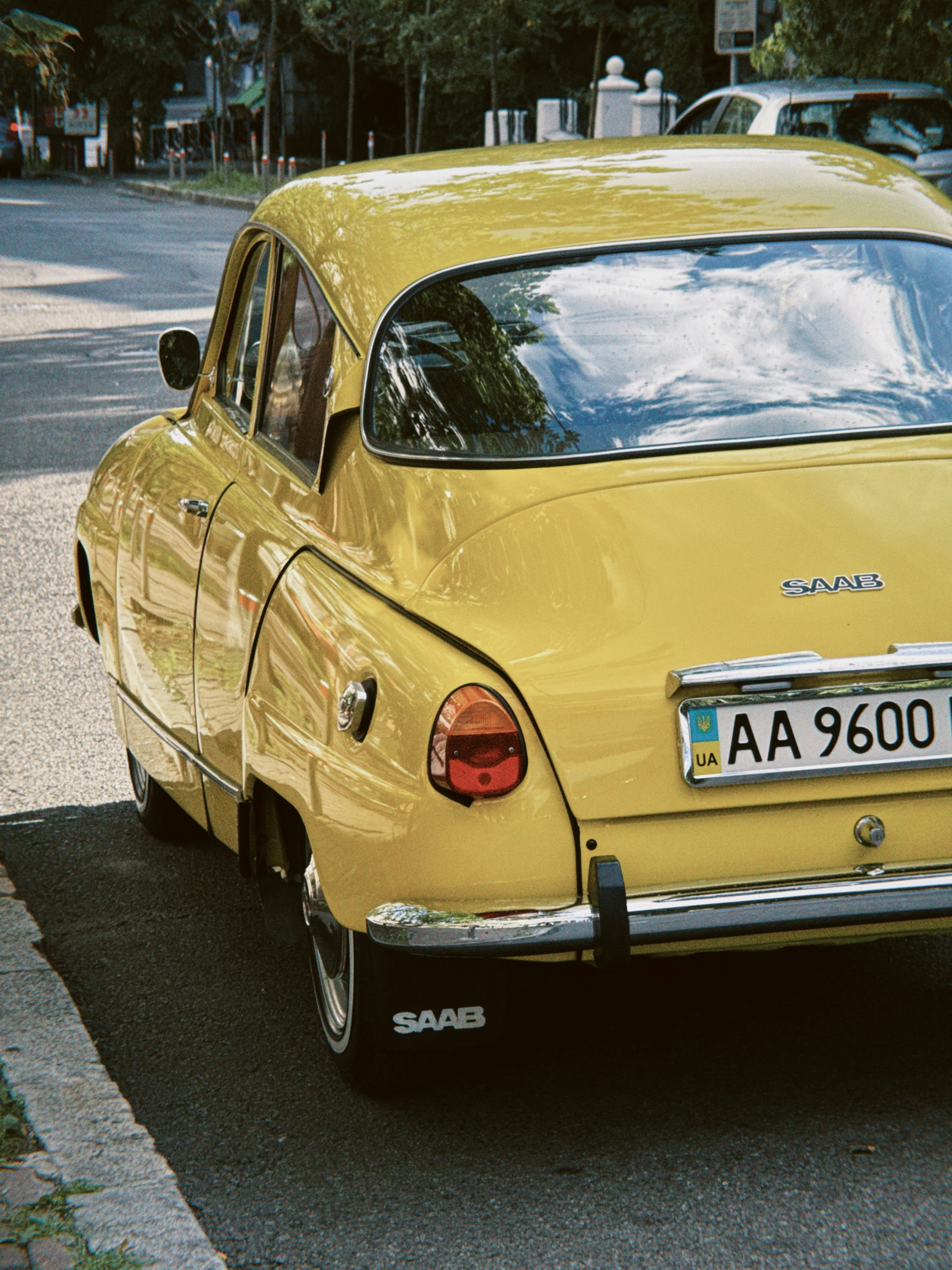 Sunlit Saab: A Vintage Yellow Ride under a Shaded Street