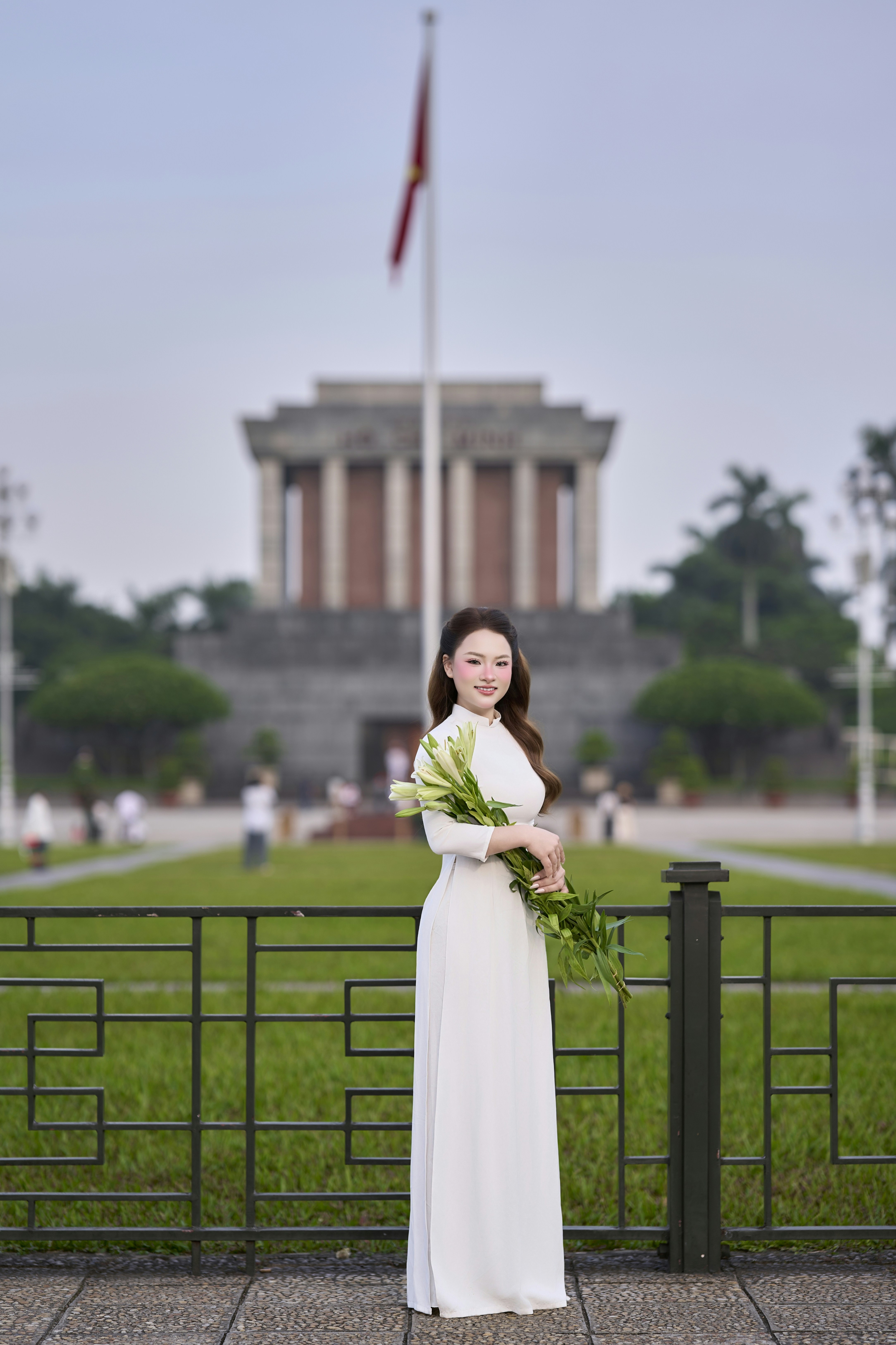 Elegance in White: A Floral Stance Before a Monumental Gate
