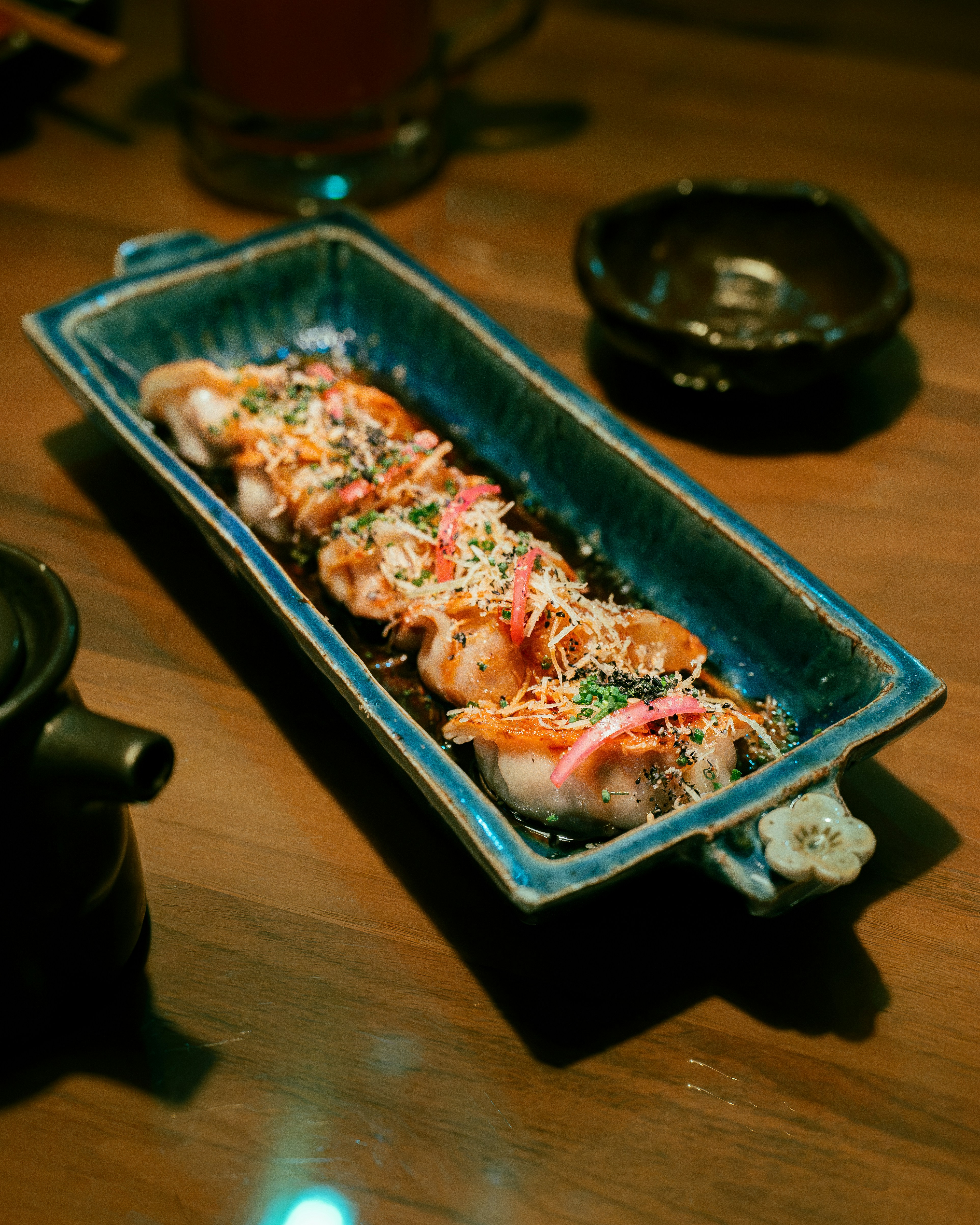 Sushi roll platter in a glossy blue ceramic boat under warm bar lighting