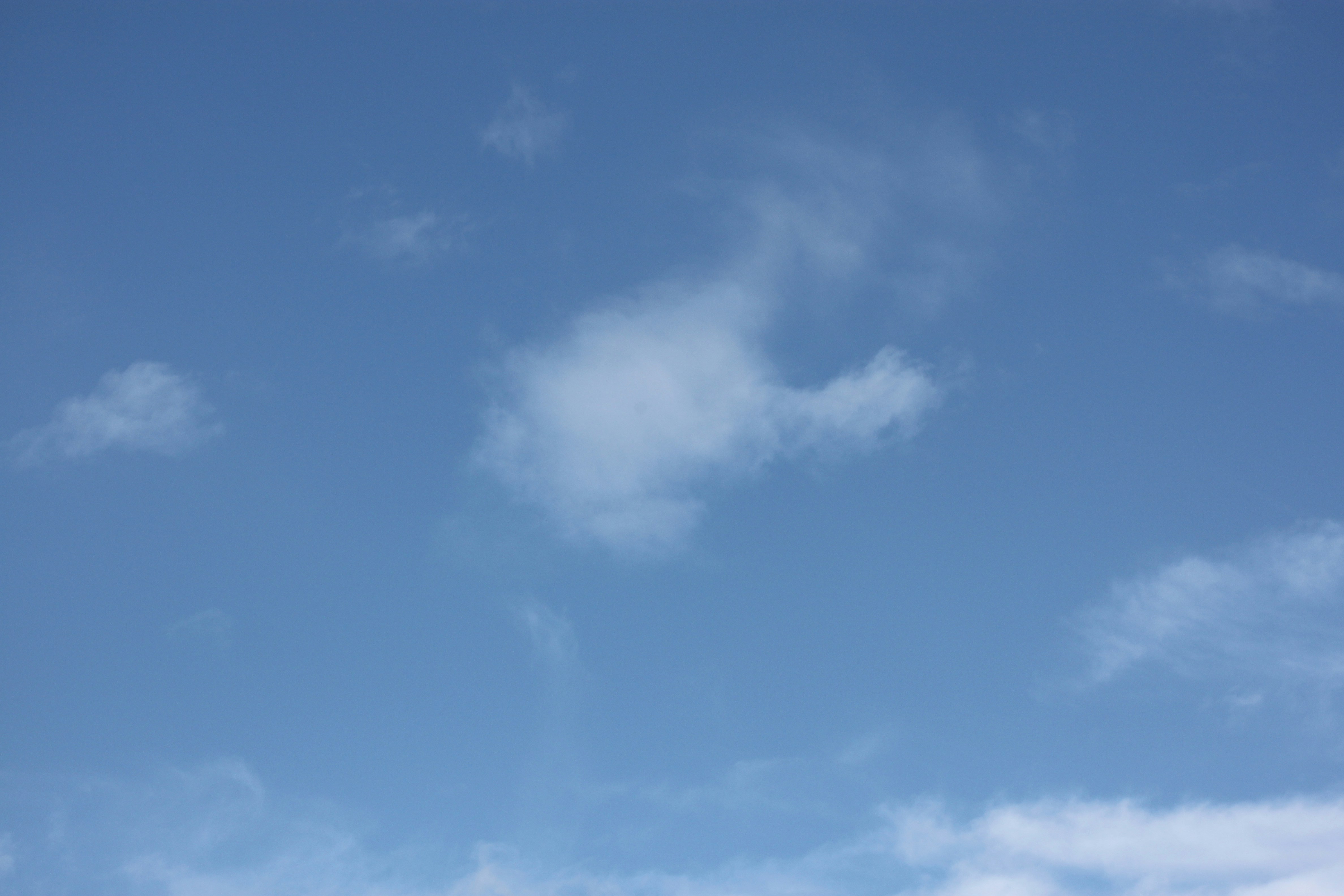 Sparse clouds drift across a calm blue sky, emphasizing negative space and openness.