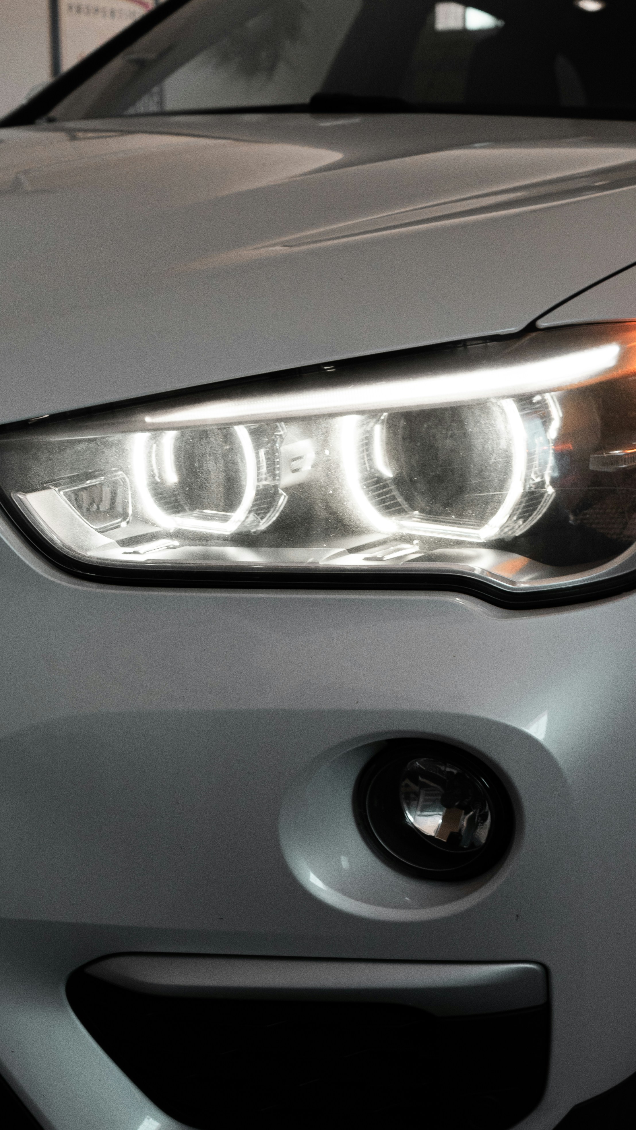 Close-up of a modern car headlamp and grille in soft studio light
