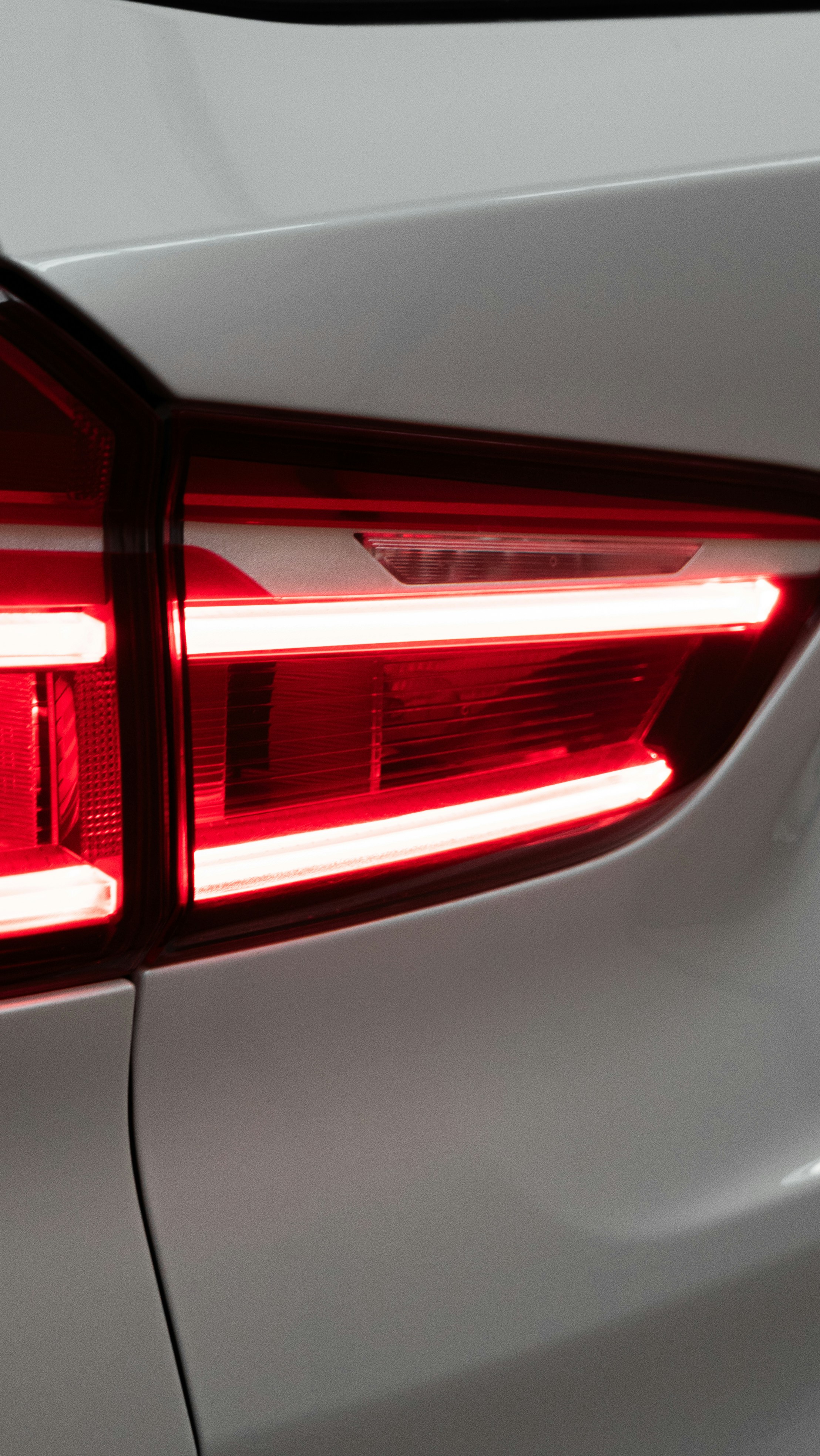 Tail Light Symphony: A White Car’s Neon Glow