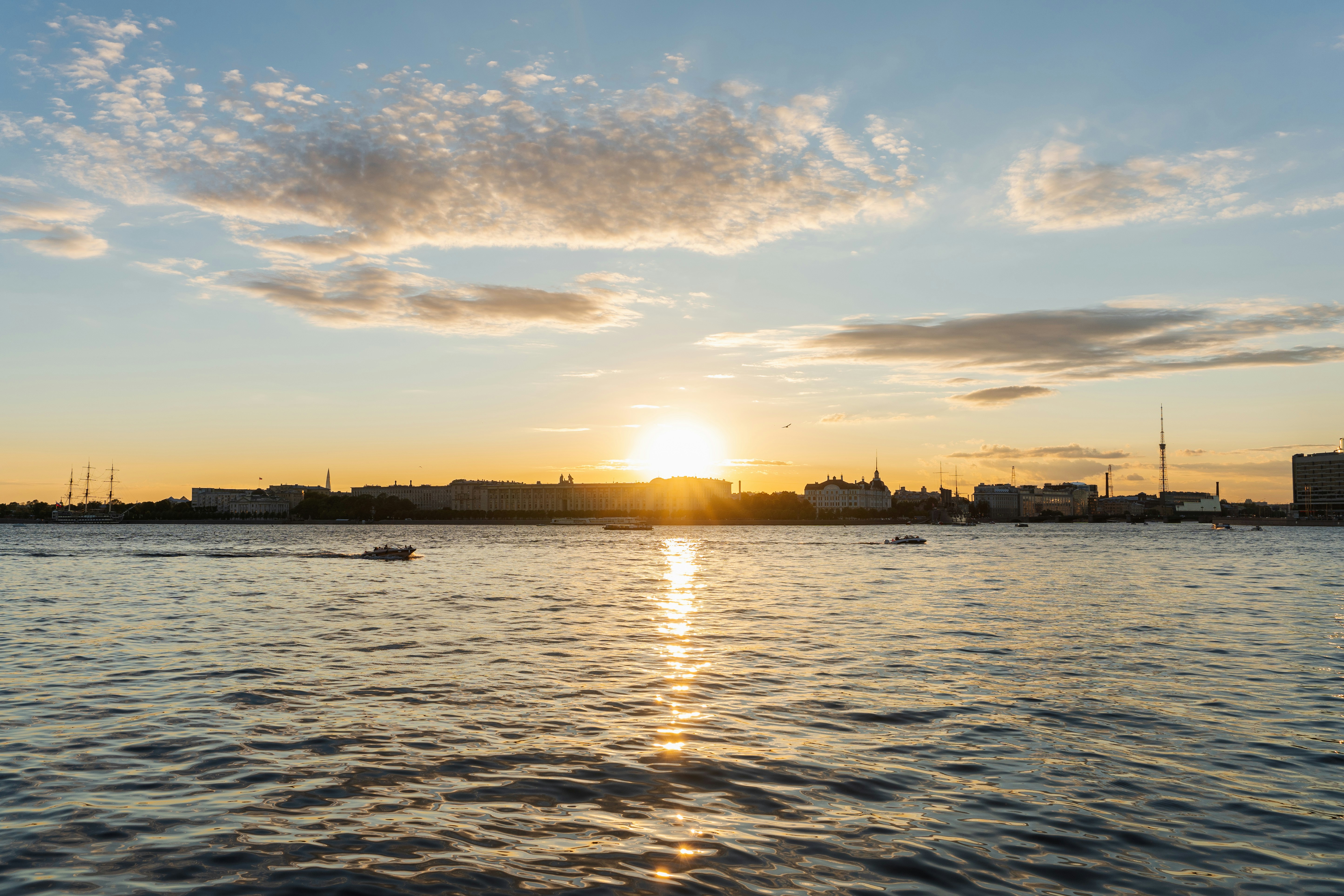 Sunlit Strait at Dusk: City Silhouette and Golden Ripples