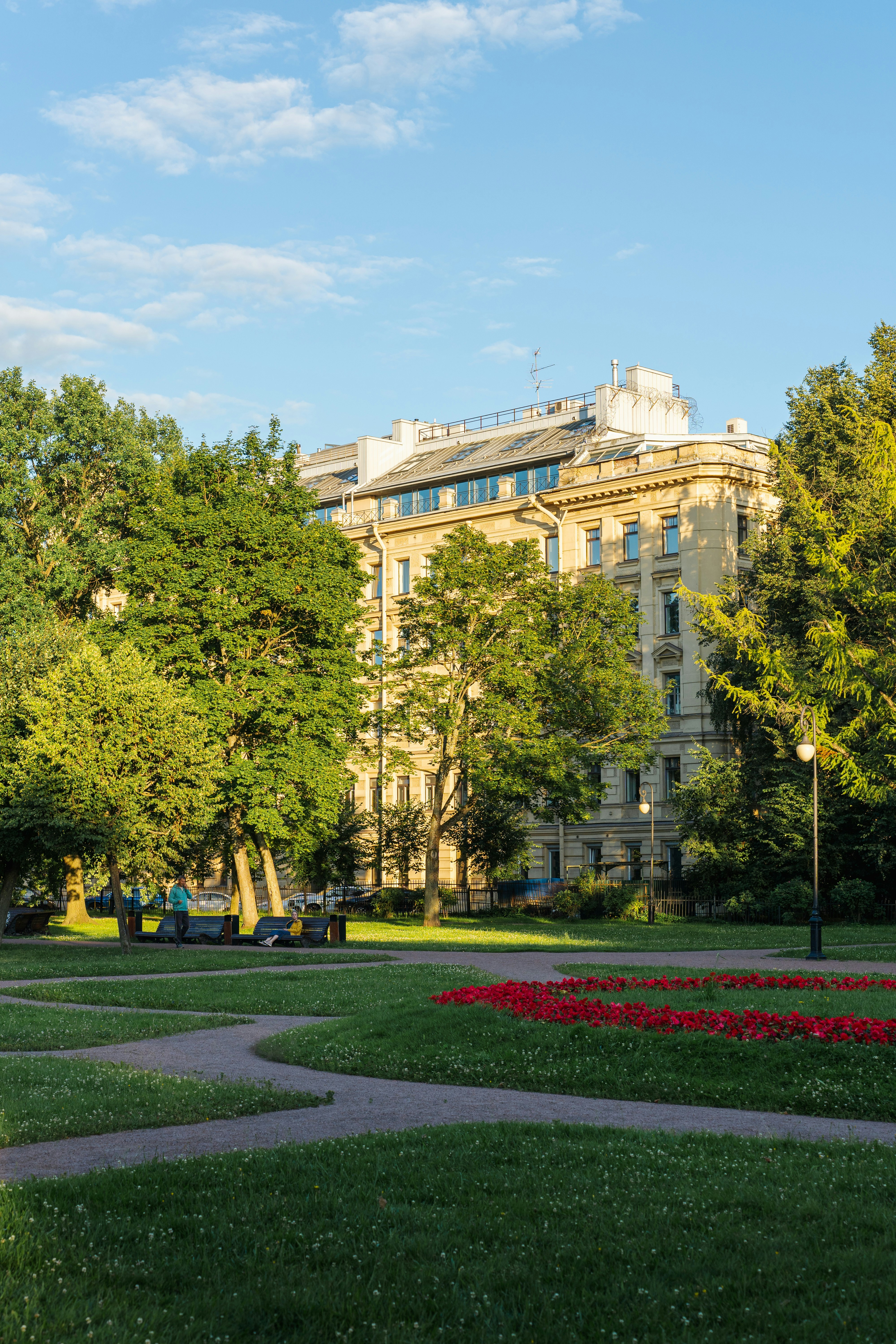 Sunlit Courtyard Bustle: City Building Framed by Verdant Trees