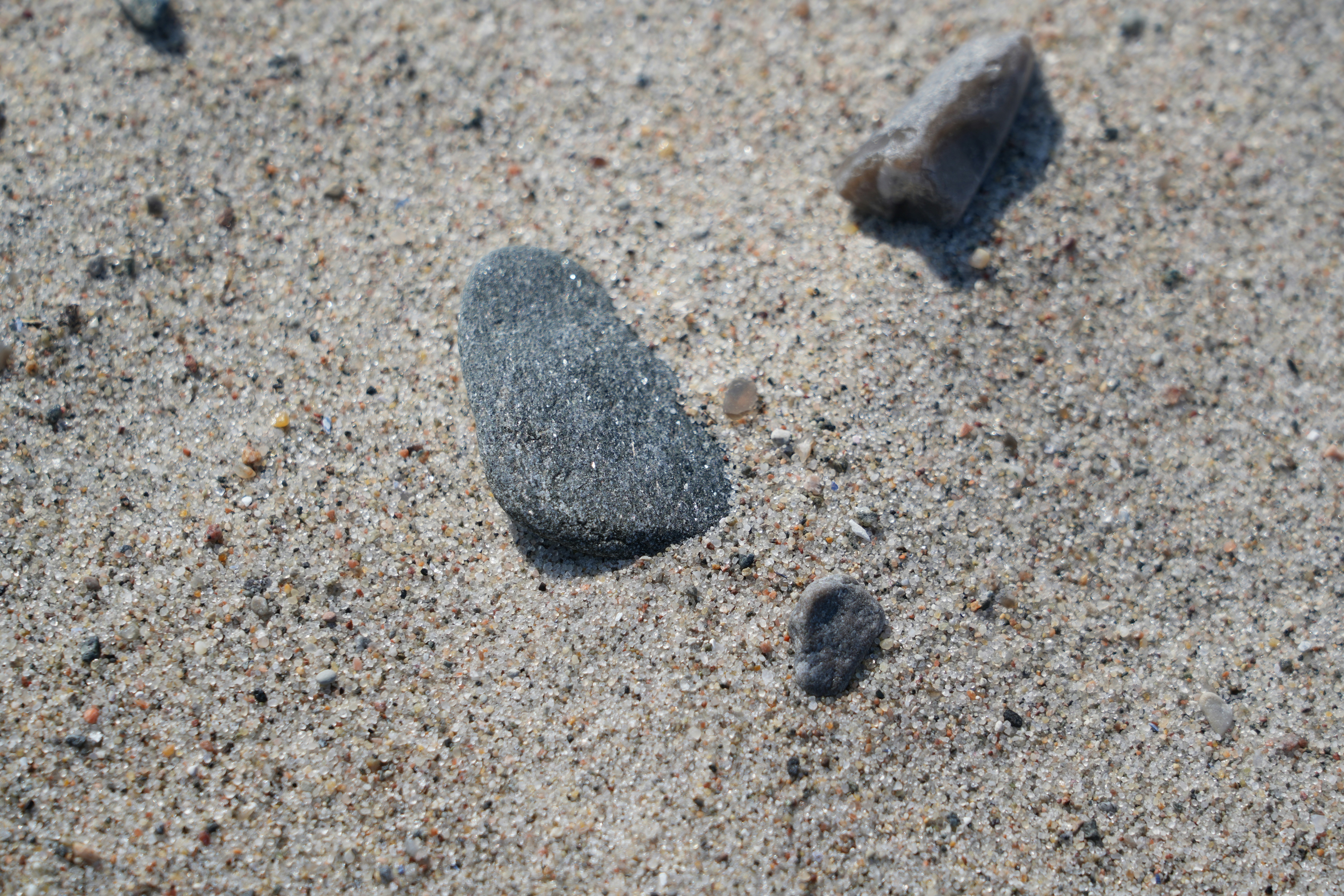 Pebble Portrait: A trio of stones on sunlit sand