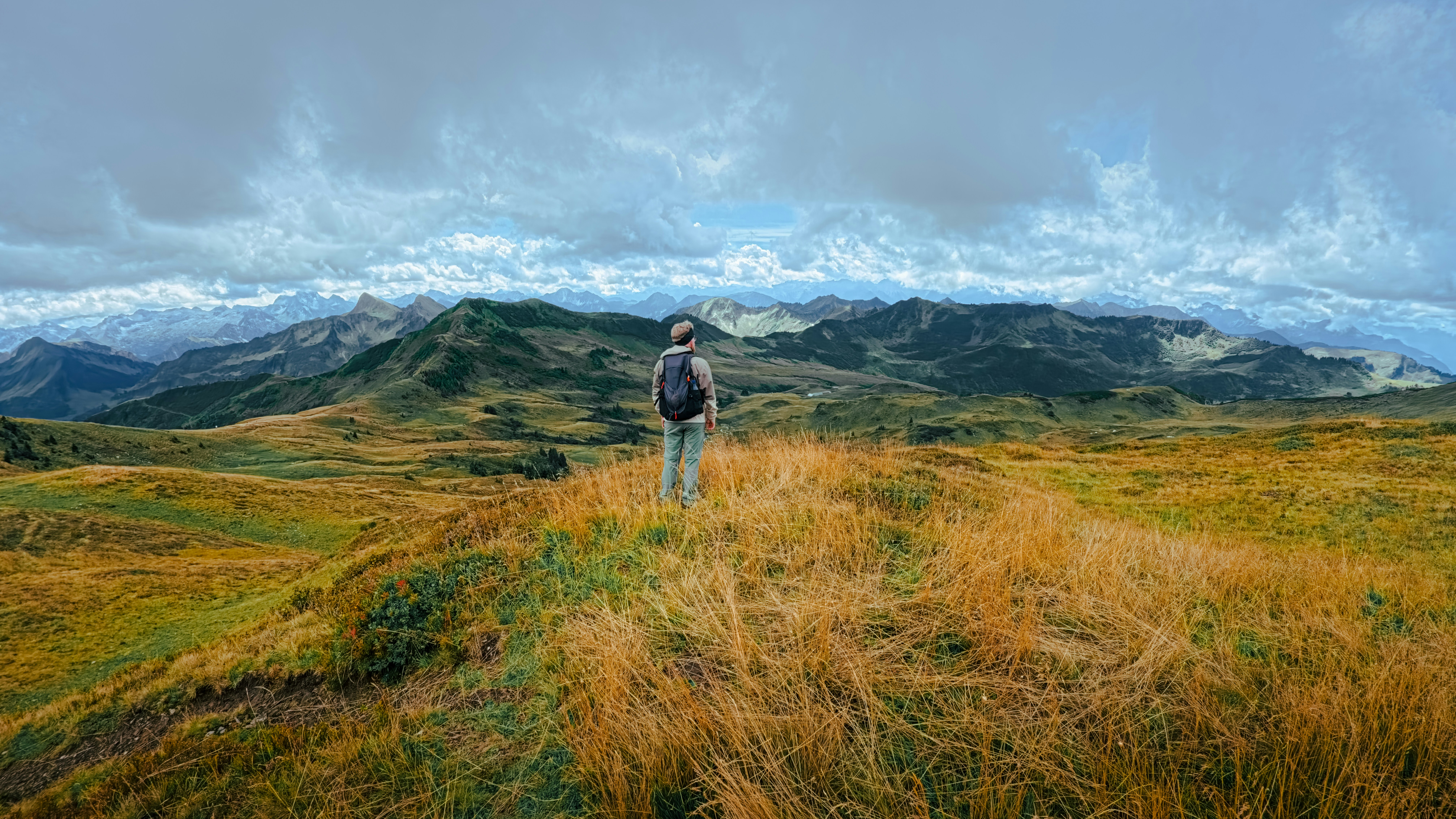 Hiker on a Golden Tussock Ridge Beneath Vast Alpine Skies