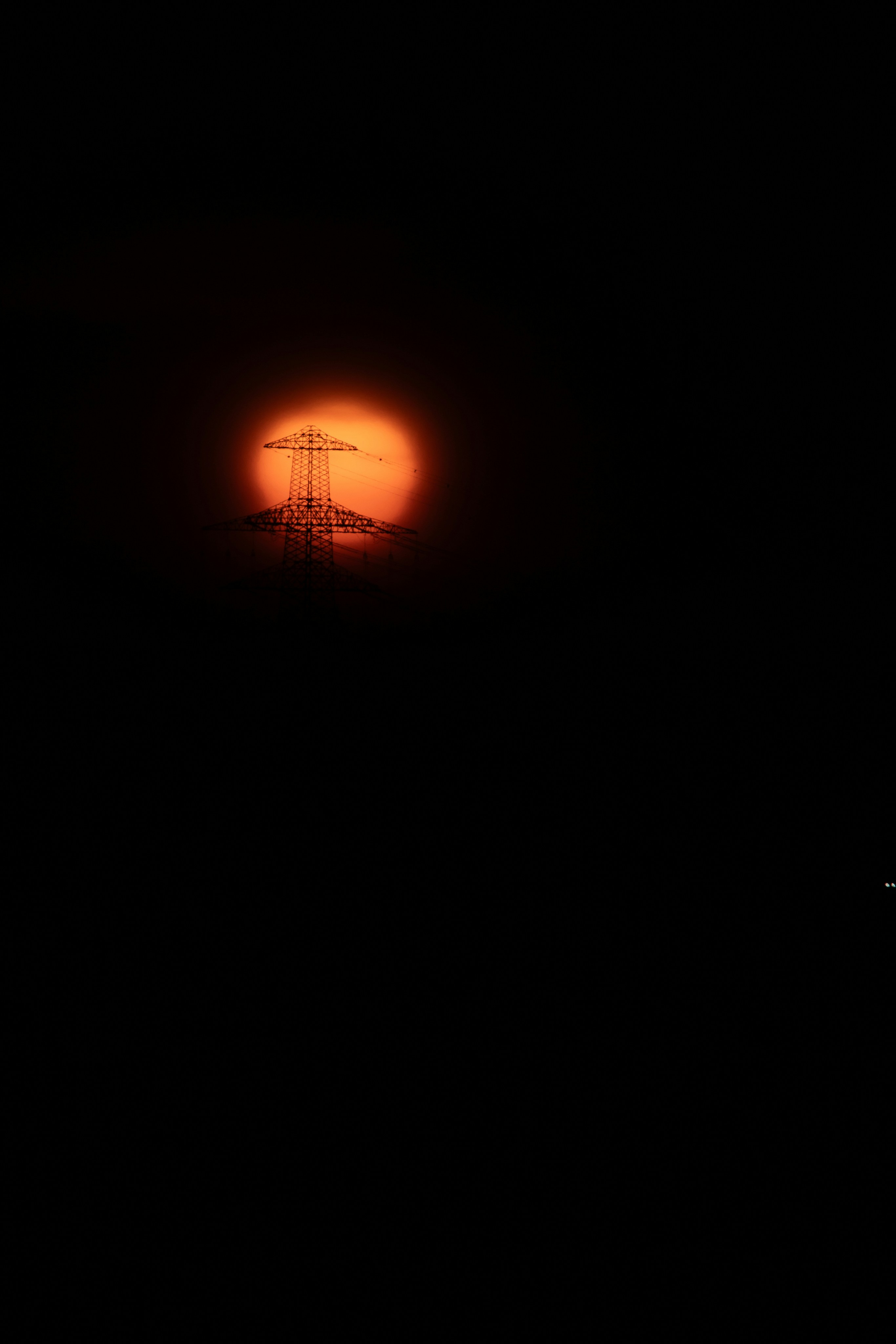 Sunlit silhouette of a lattice tower carved into a fiery horizon