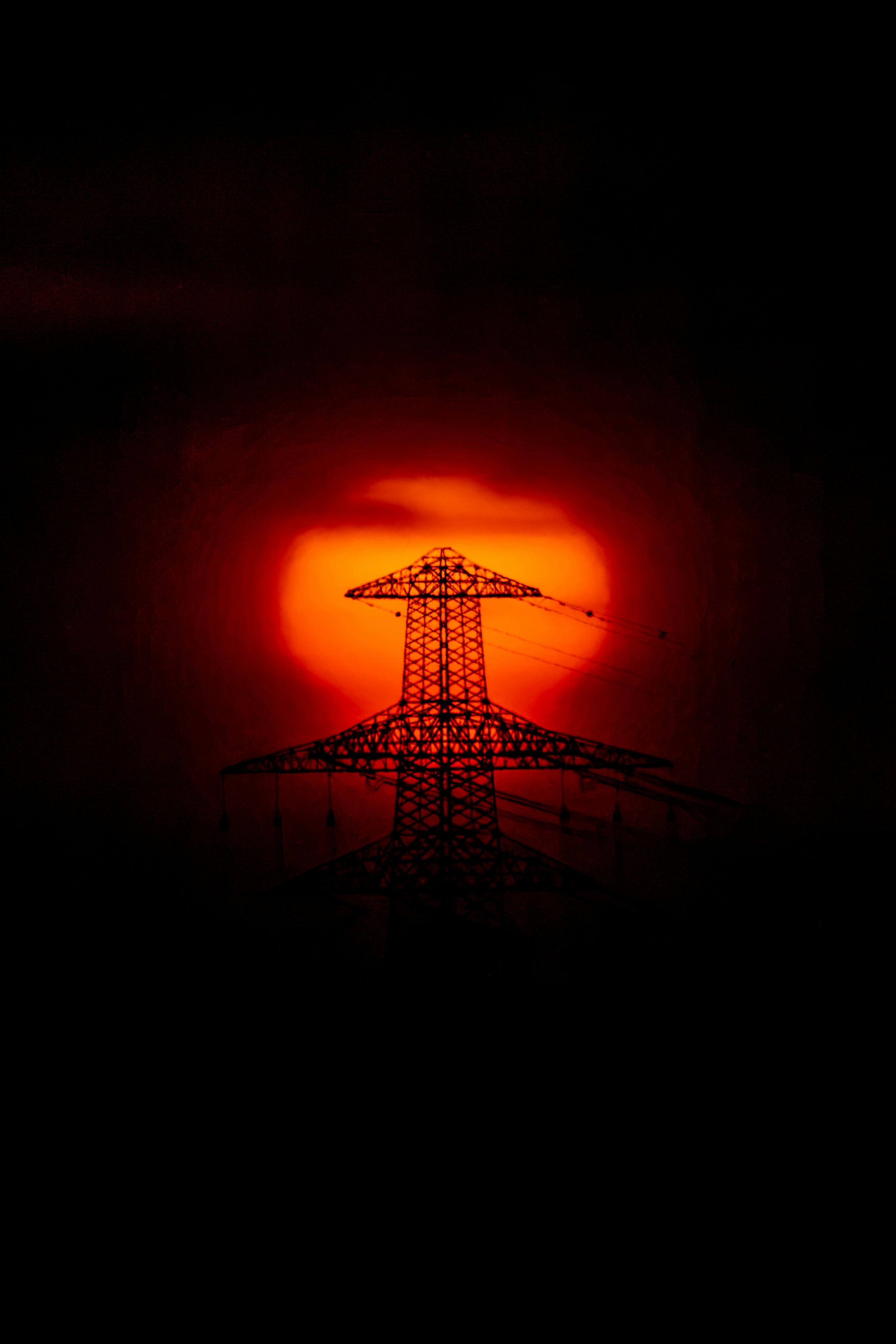 Sunlit Lattice: Tower Silhouette against a Looming Red Ember