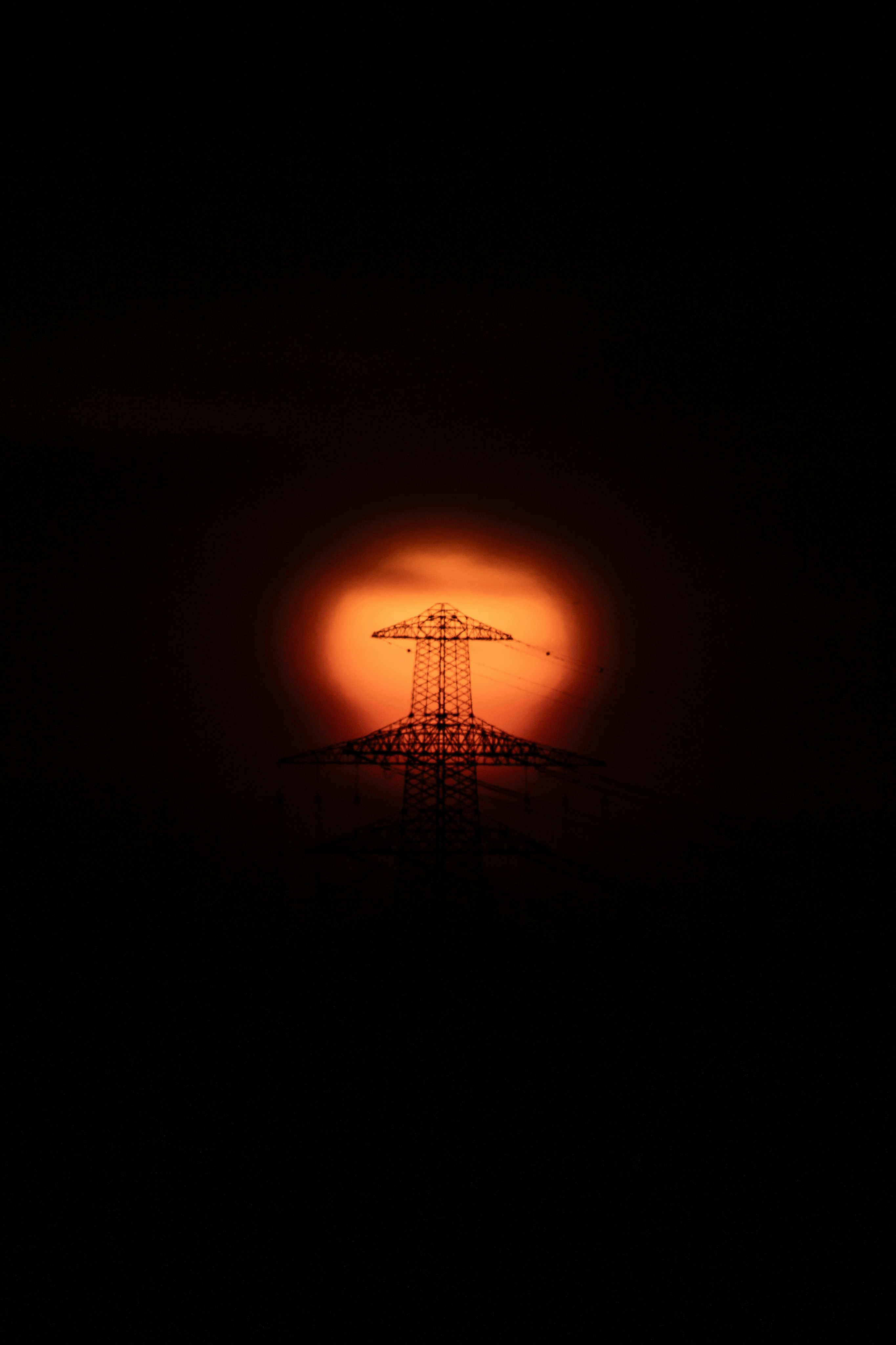 Sunlit silhouette: transmission tower framed by a glowing solar halo
