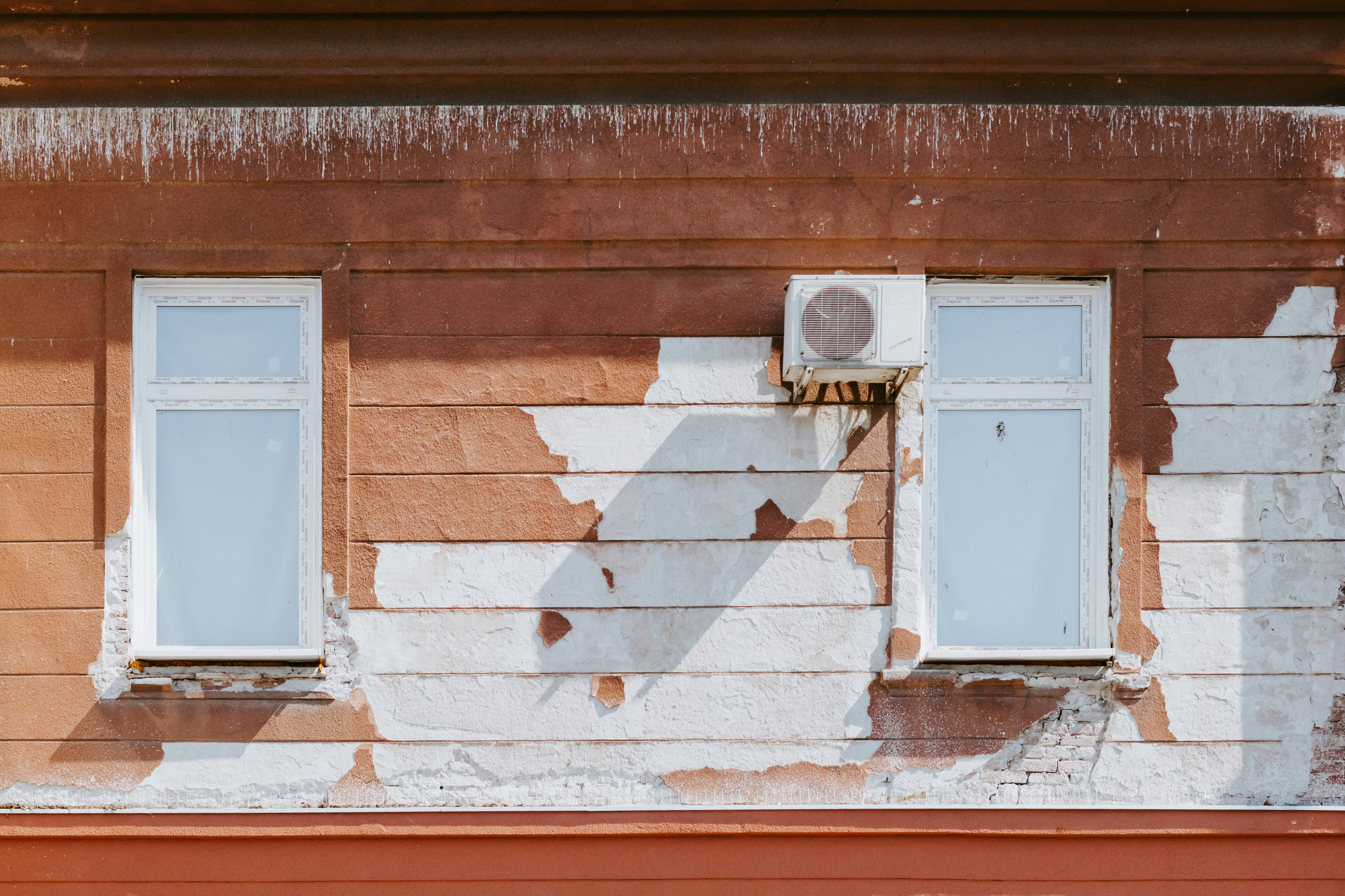 Weathered Brick Facade with Deteriorating Paint and Air Conditioner