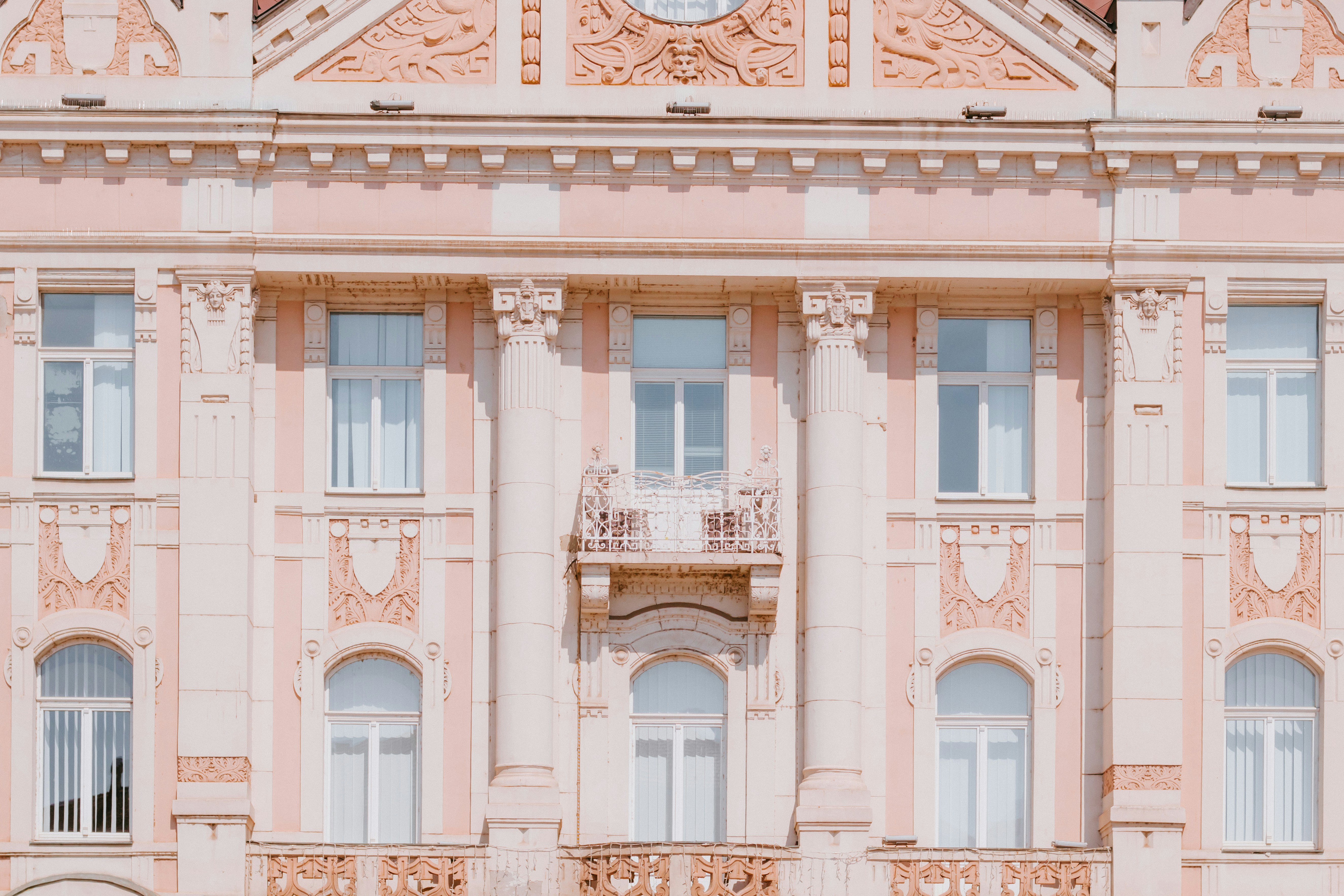 Symmetry in Rose-Tinted Facade: A Close-Viewed Balcony atop a Historic Elevation