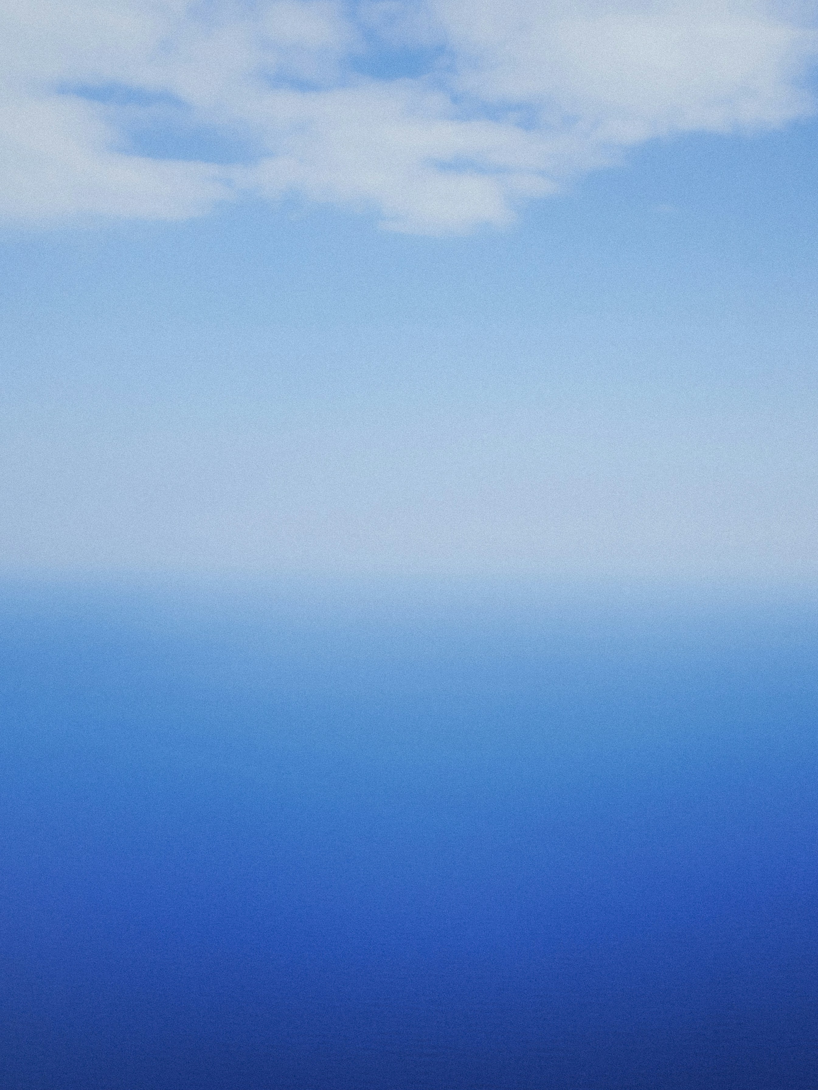 Soft gradient seascape with a subtle horizon and minimal cloud detail, emphasizing calm blue tones and atmospheric depth.