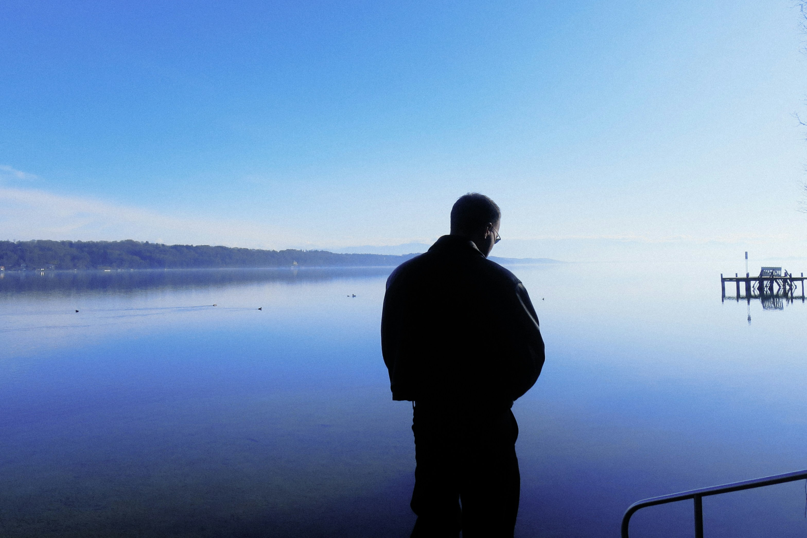 Silhouette at the Lake: A Figure Contemplates the Calm Horizon