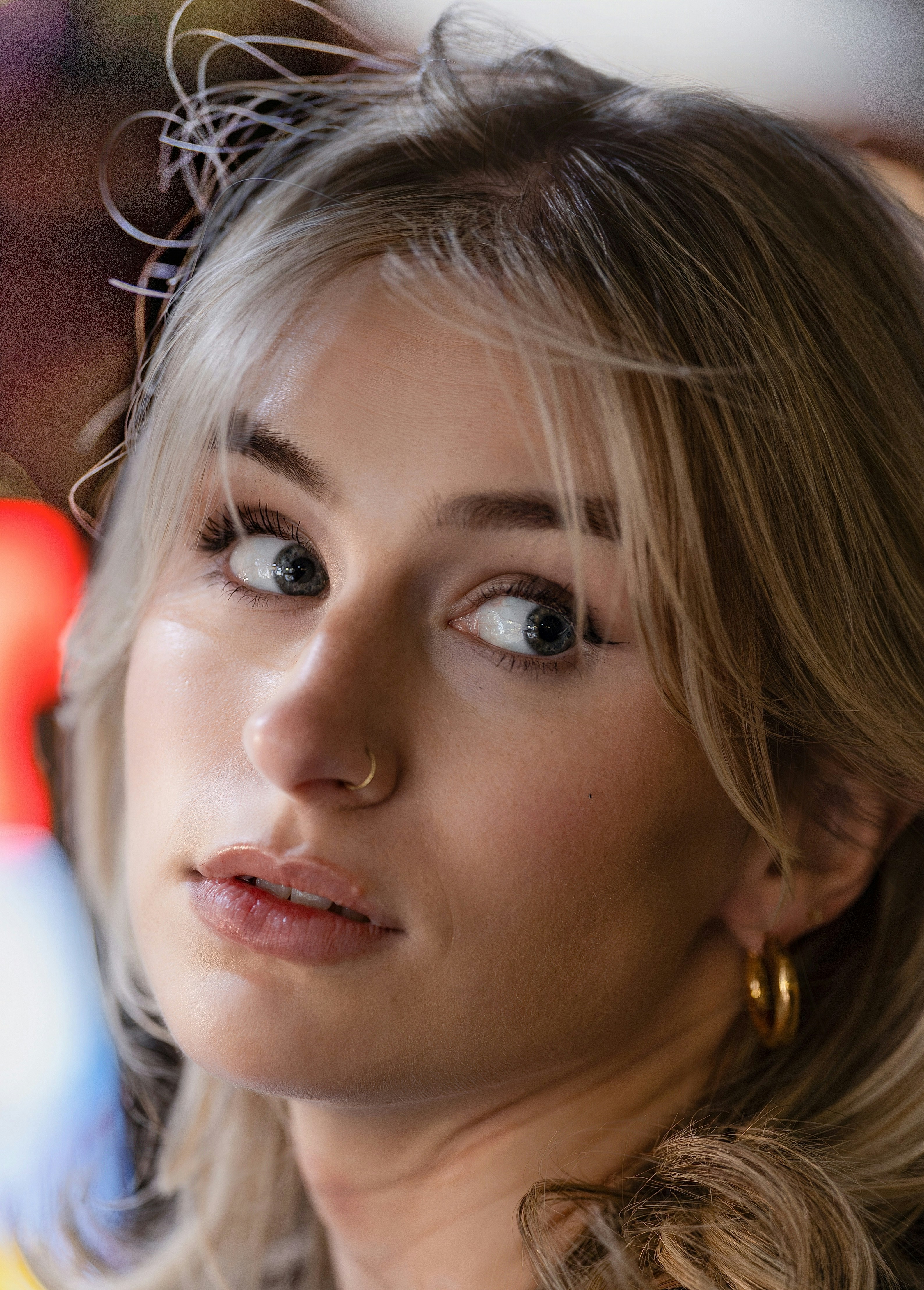 Close-up of a thoughtful woman with piercing eyes and a subtle nose ring, bathed in soft, warm light; the portrait emphasizes her expression and facial features. This is a candid, lifestyle shot.