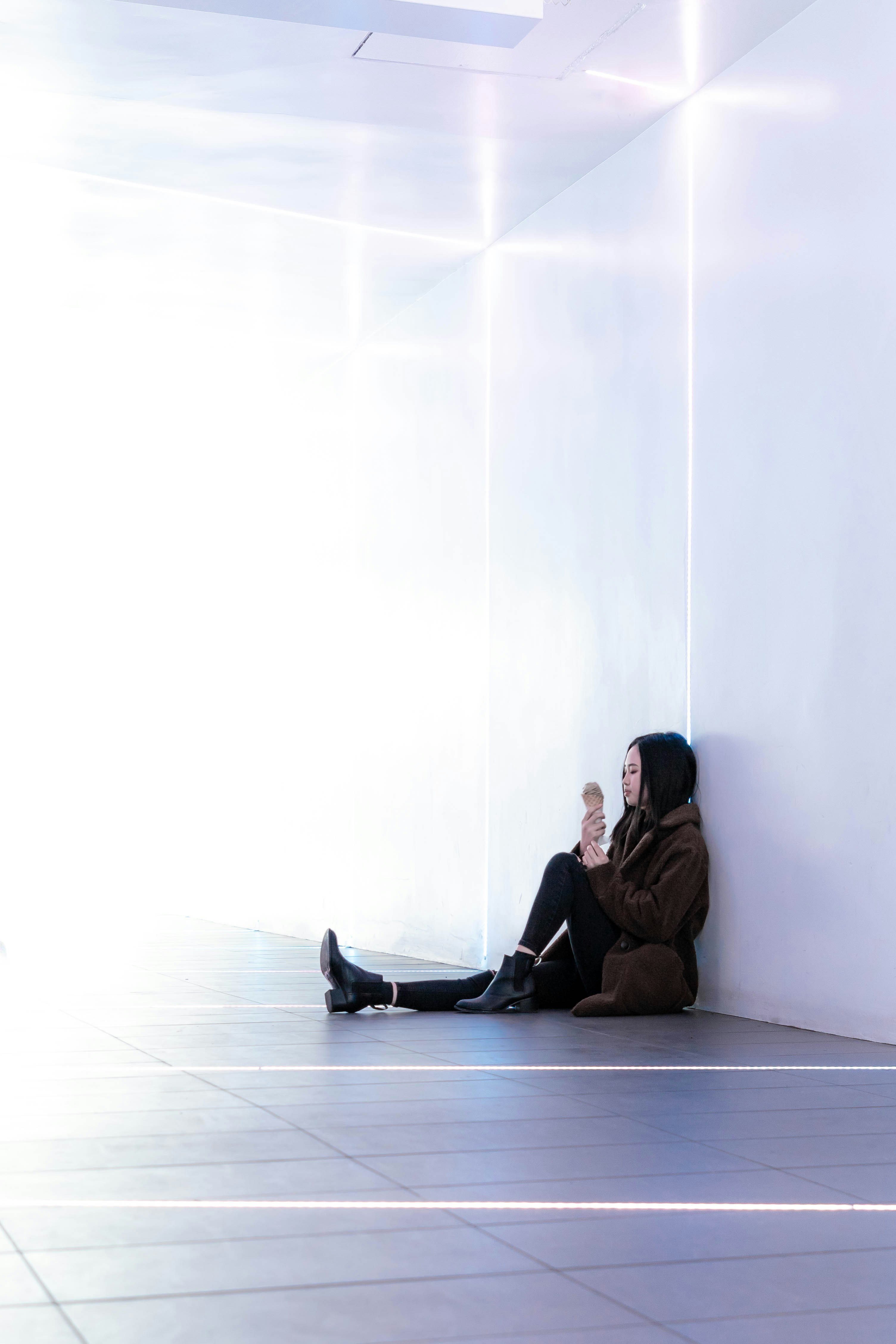 Icebox Refuge: A lone figure in a luminous corridor savoring a quiet ice-cream moment