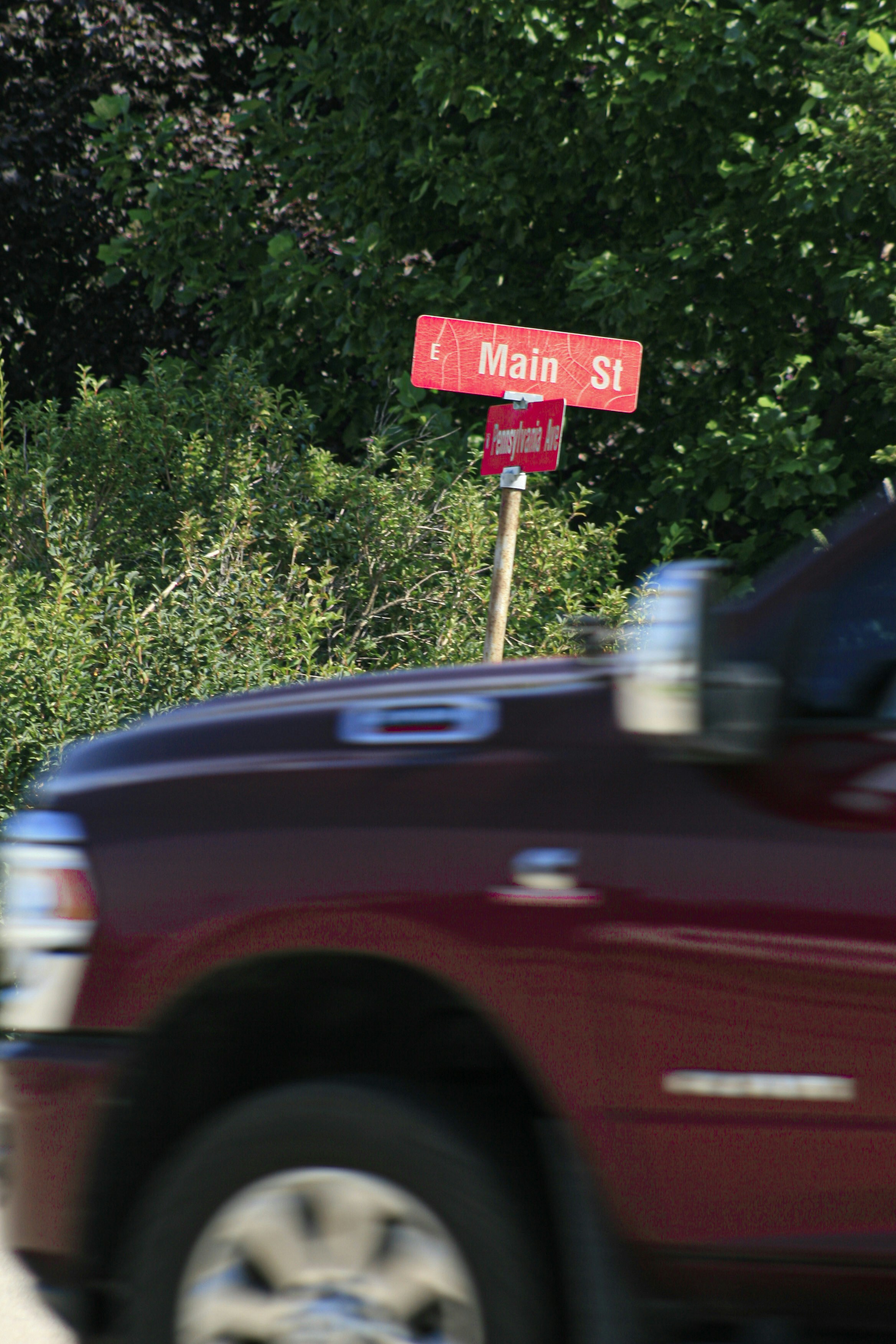 Street Sign Stop: Red Main Street Marker Looms Over a Moving Pickup