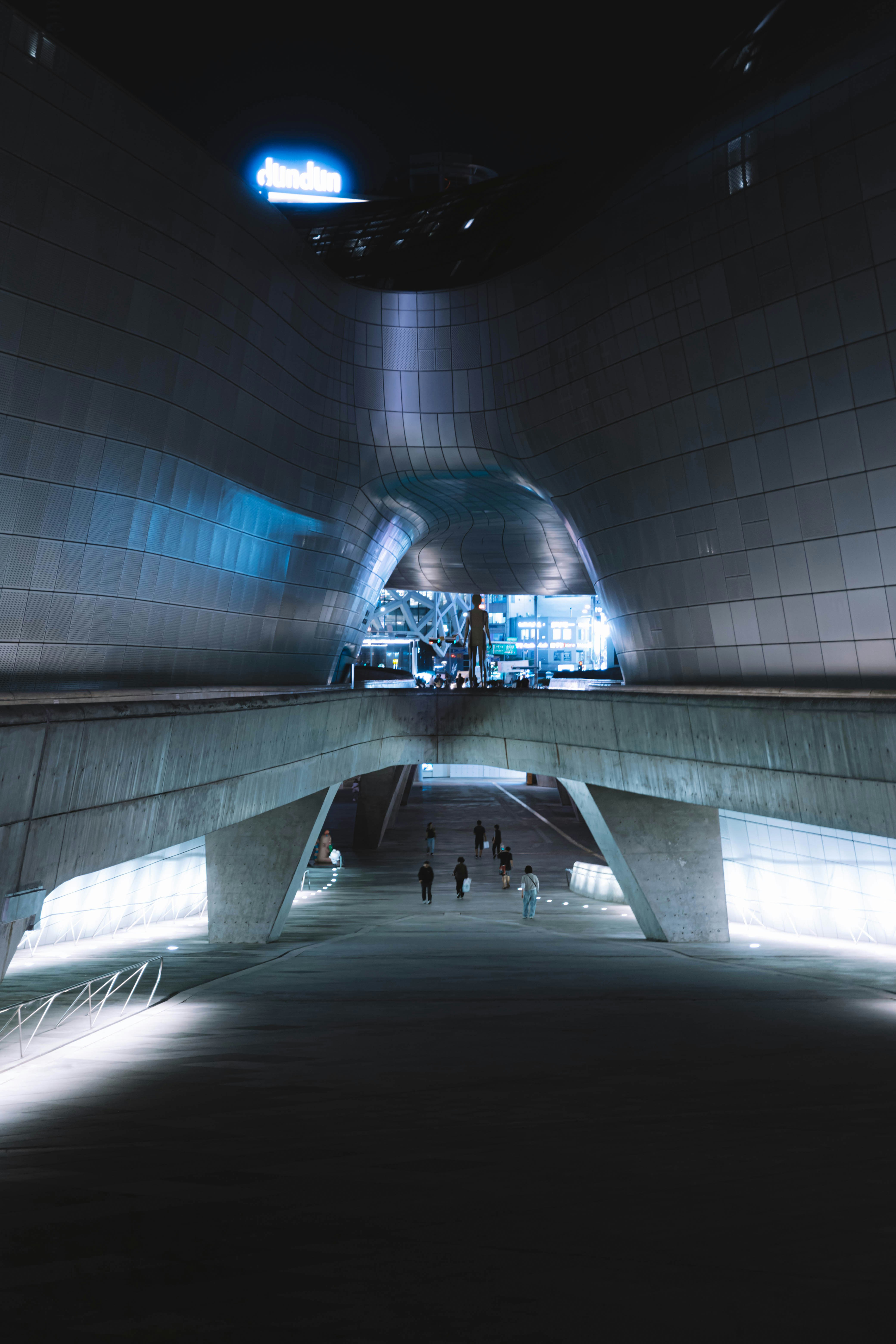 Under Urban Arcades: Neon Curves and Shadowed Walkers