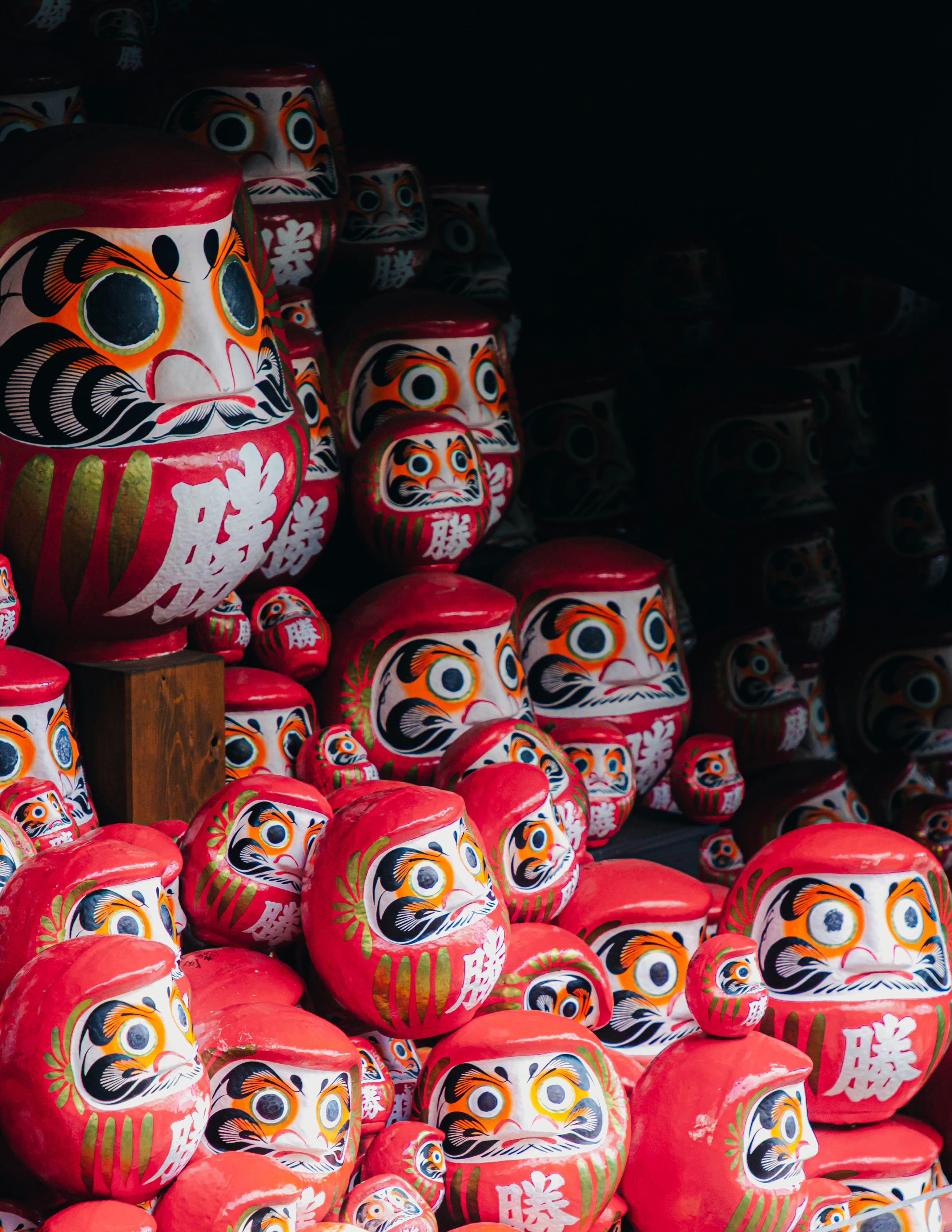 Red-Crowned Lanterns: A Clutter of Daruma Faces in Velvet Darkness