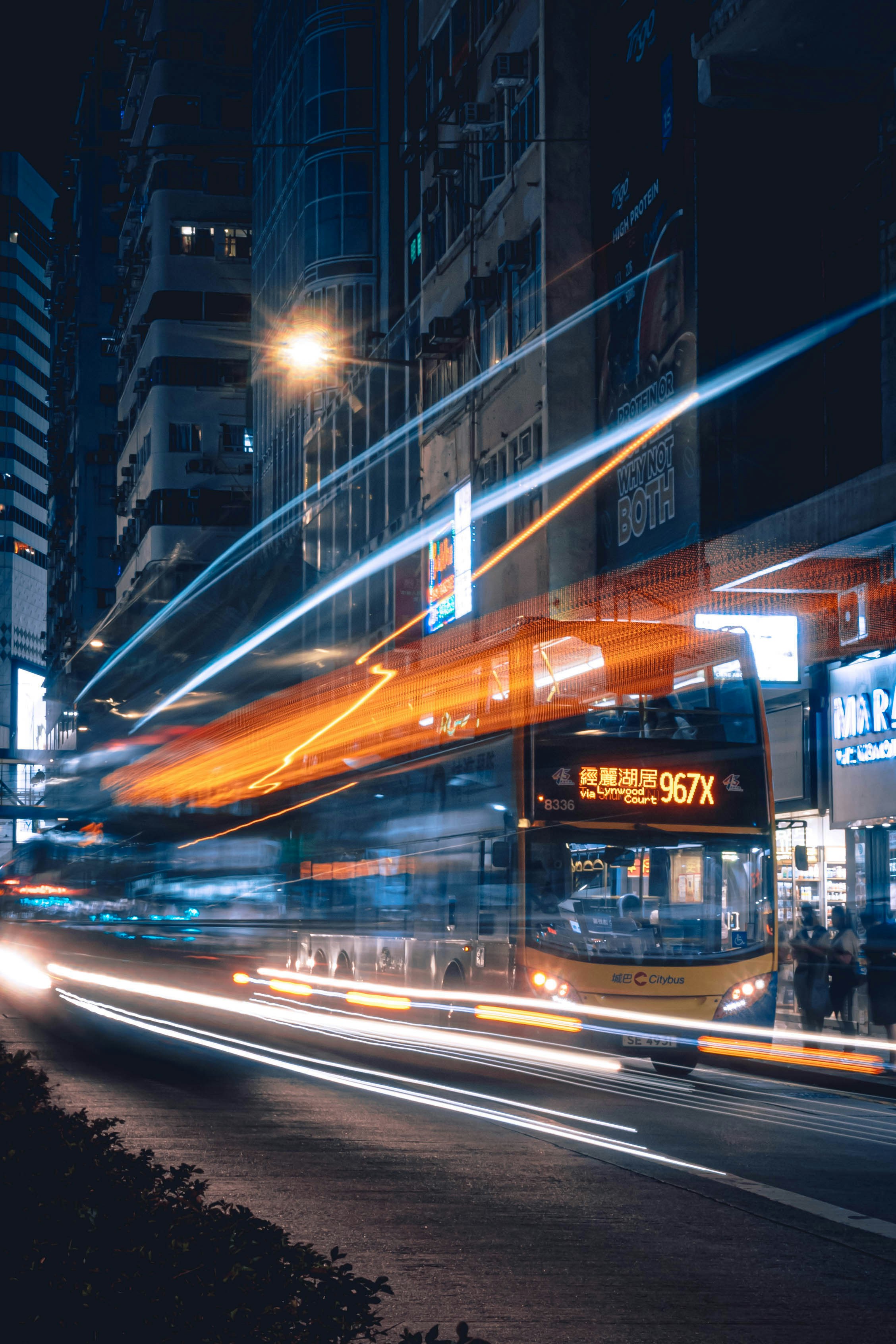 Neon Motion: Night Bus Trail Through Urban Glow
