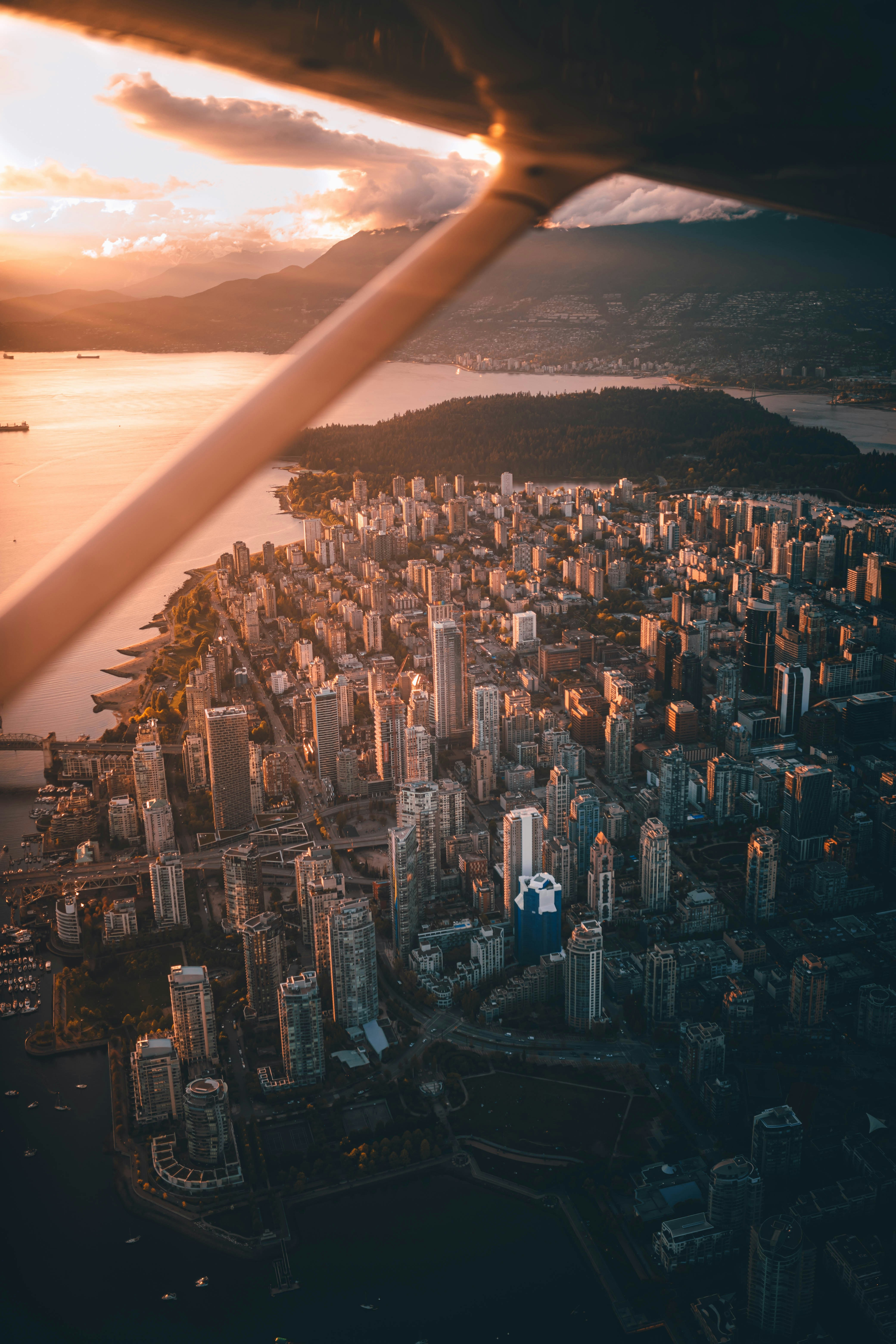 Sunlit cityscape viewed through a wing over a harbor