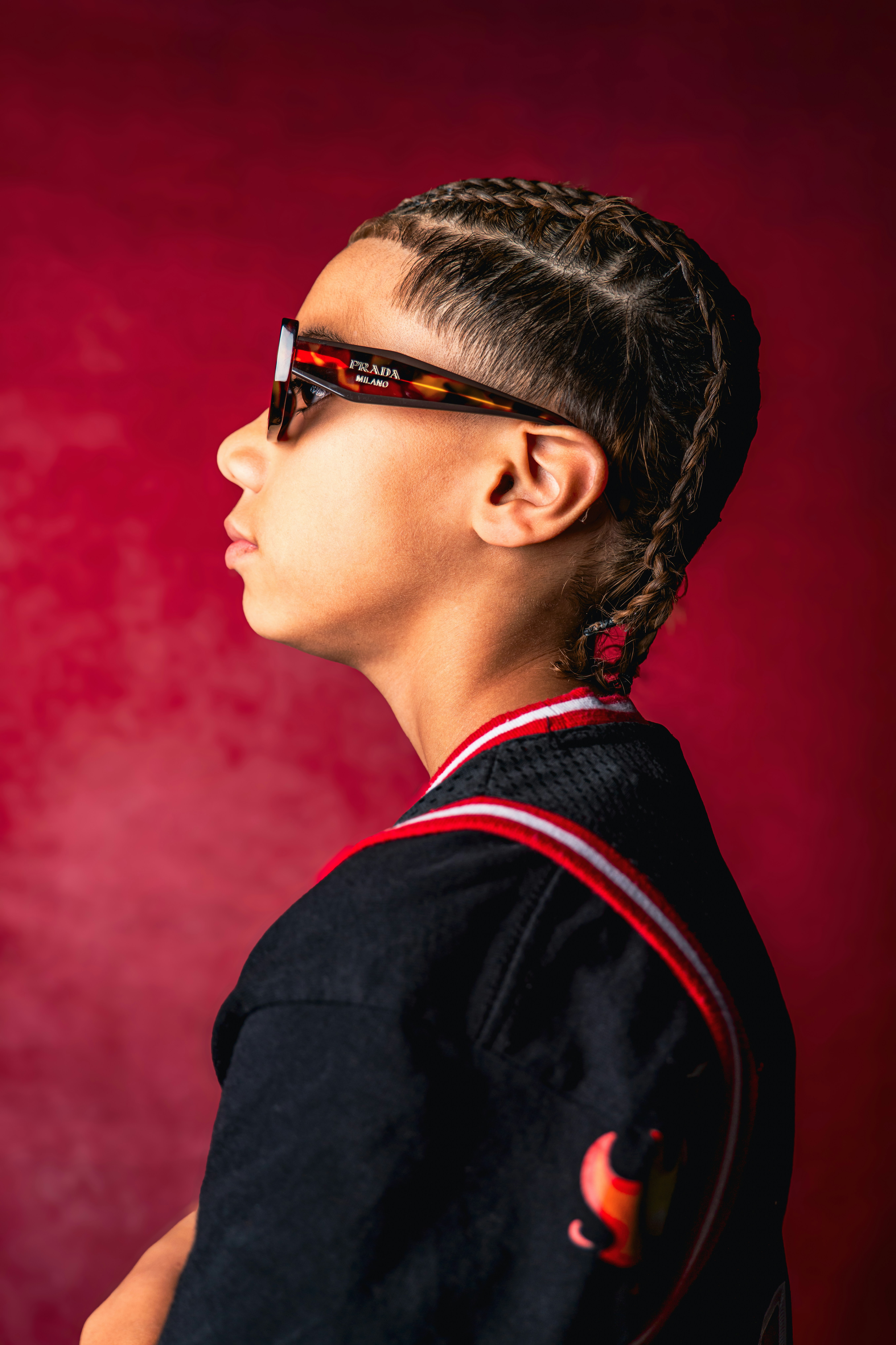Side Profile: Bold Braids and Sunglasses in Rich Red Backdrop