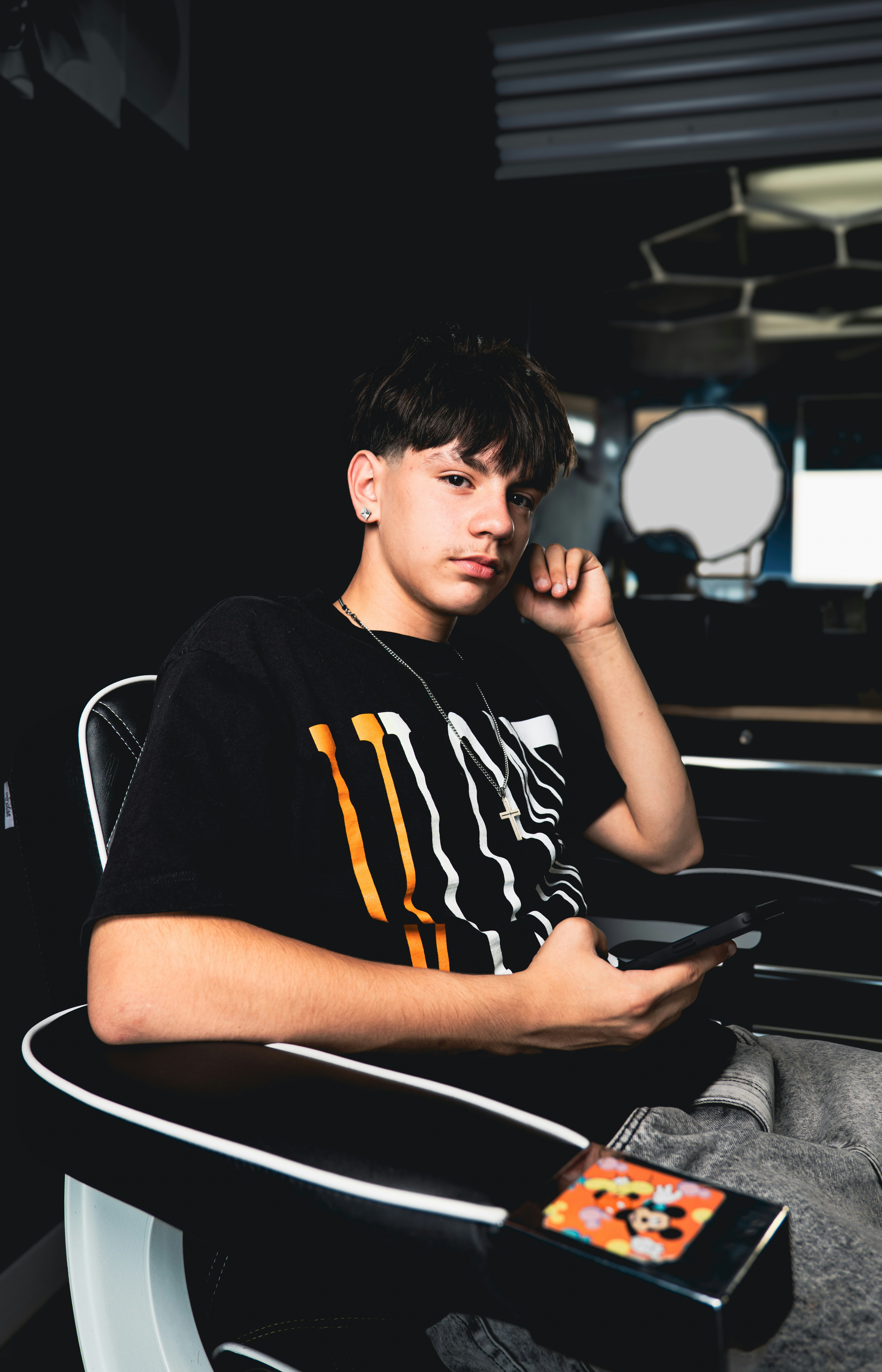 Casual studio glow: a teen sits with a phone in a modern workspace